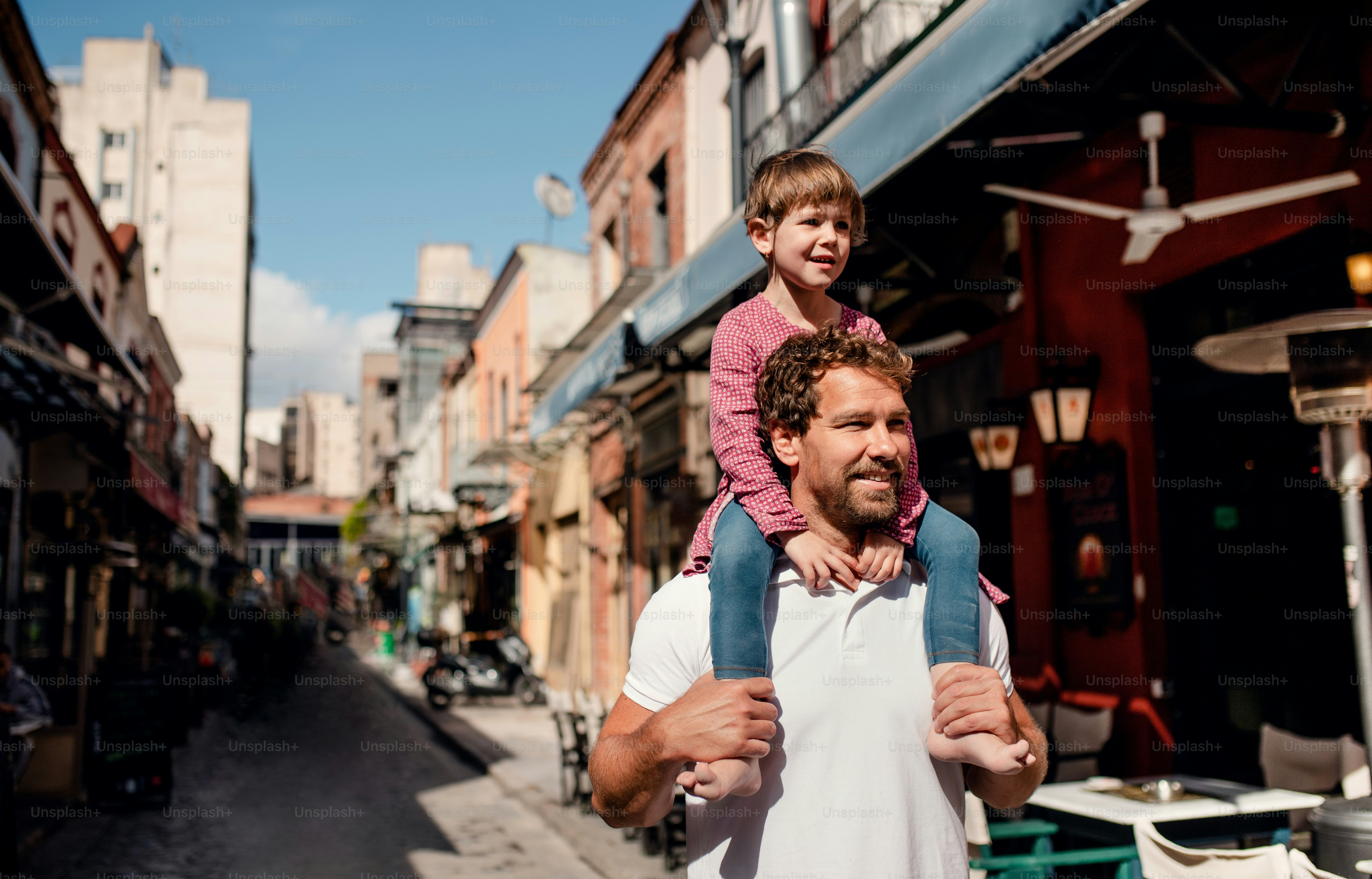 Padre con una hija pequeña de pie al aire libre en la calle en una ...