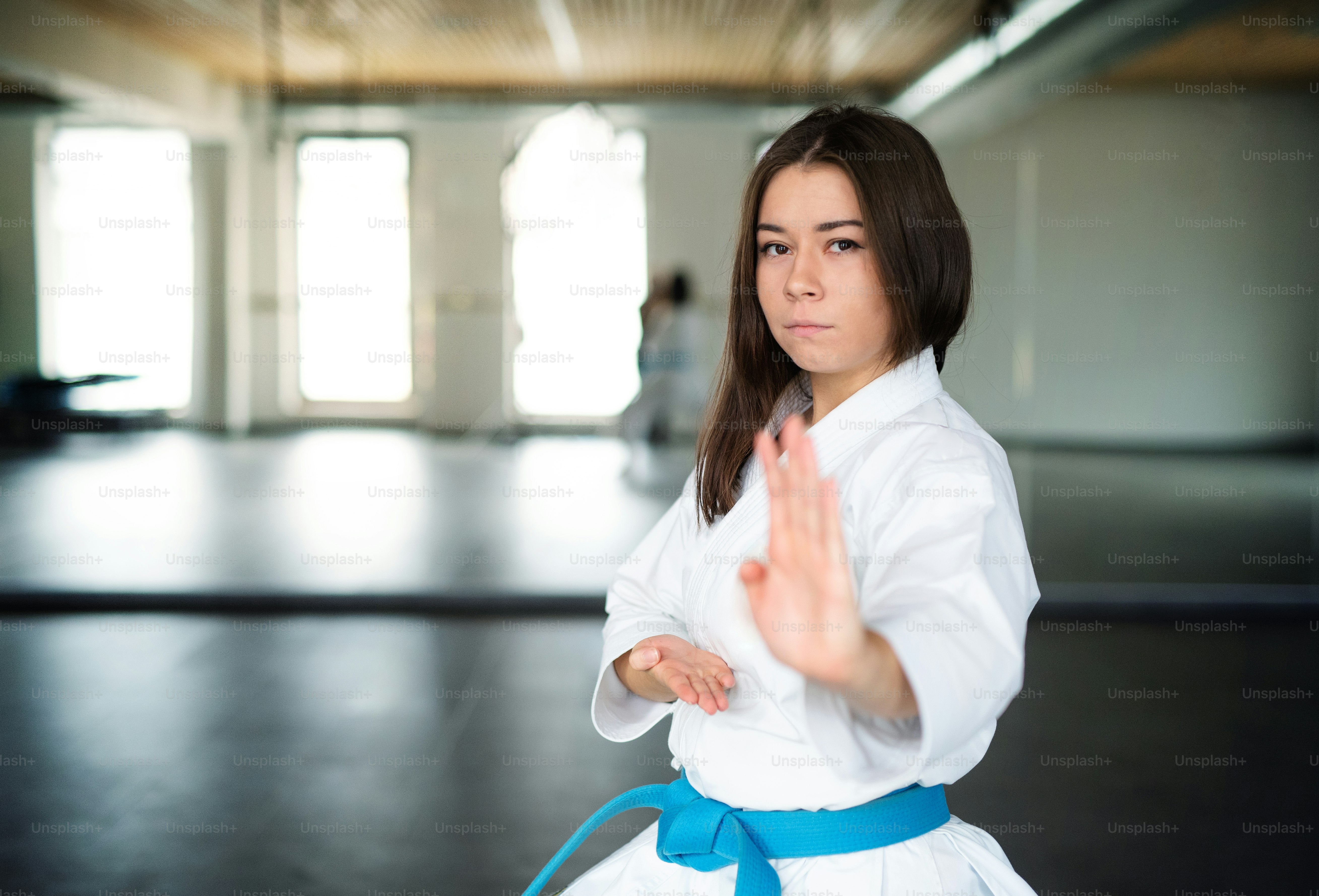 An attractive young woman practising karate indoors in gym. Copy space ...