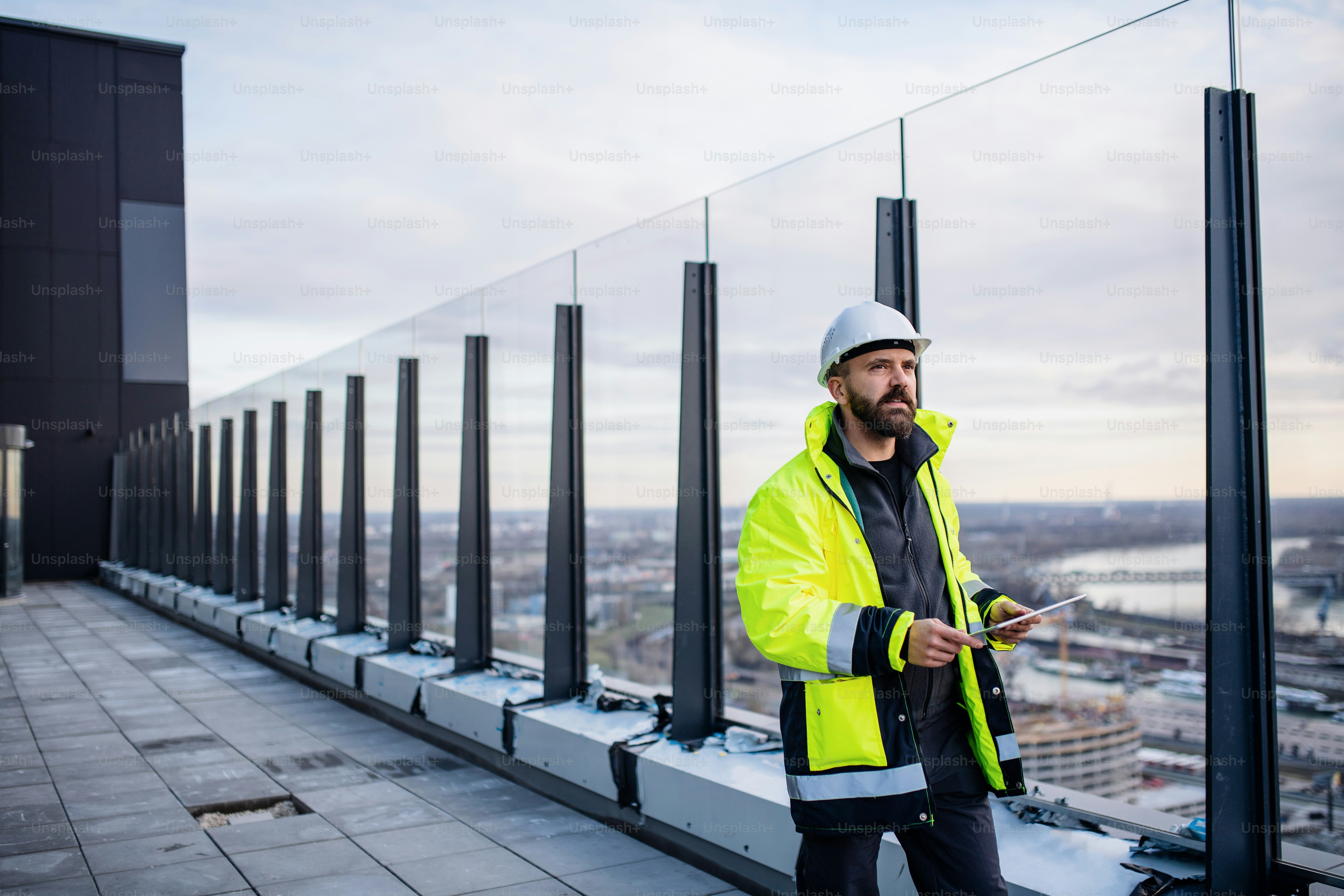 Mature man engineer standing on construction site, holding tablet with ...