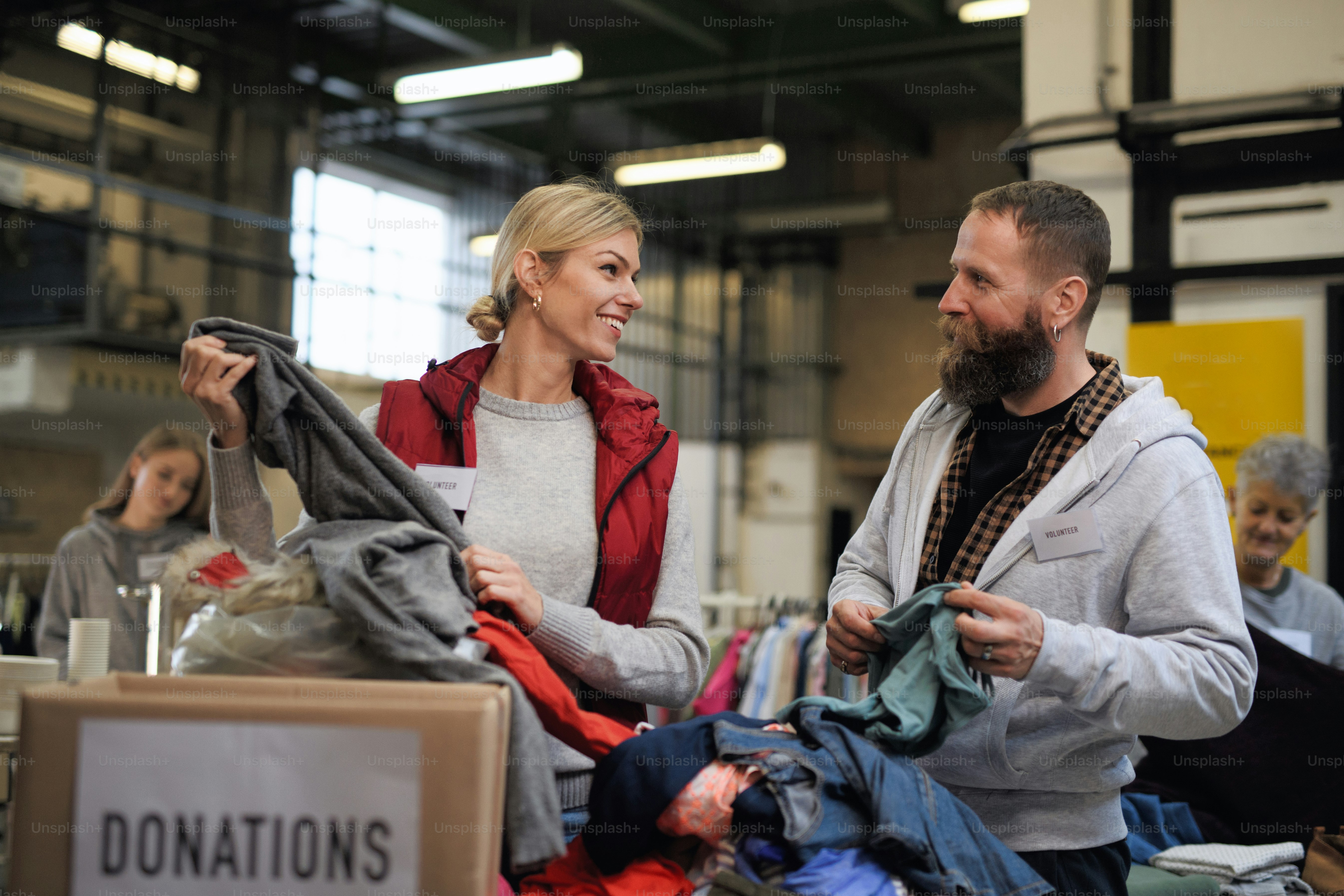 Portrait of volunteers sorting out donated clothes in community charity ...