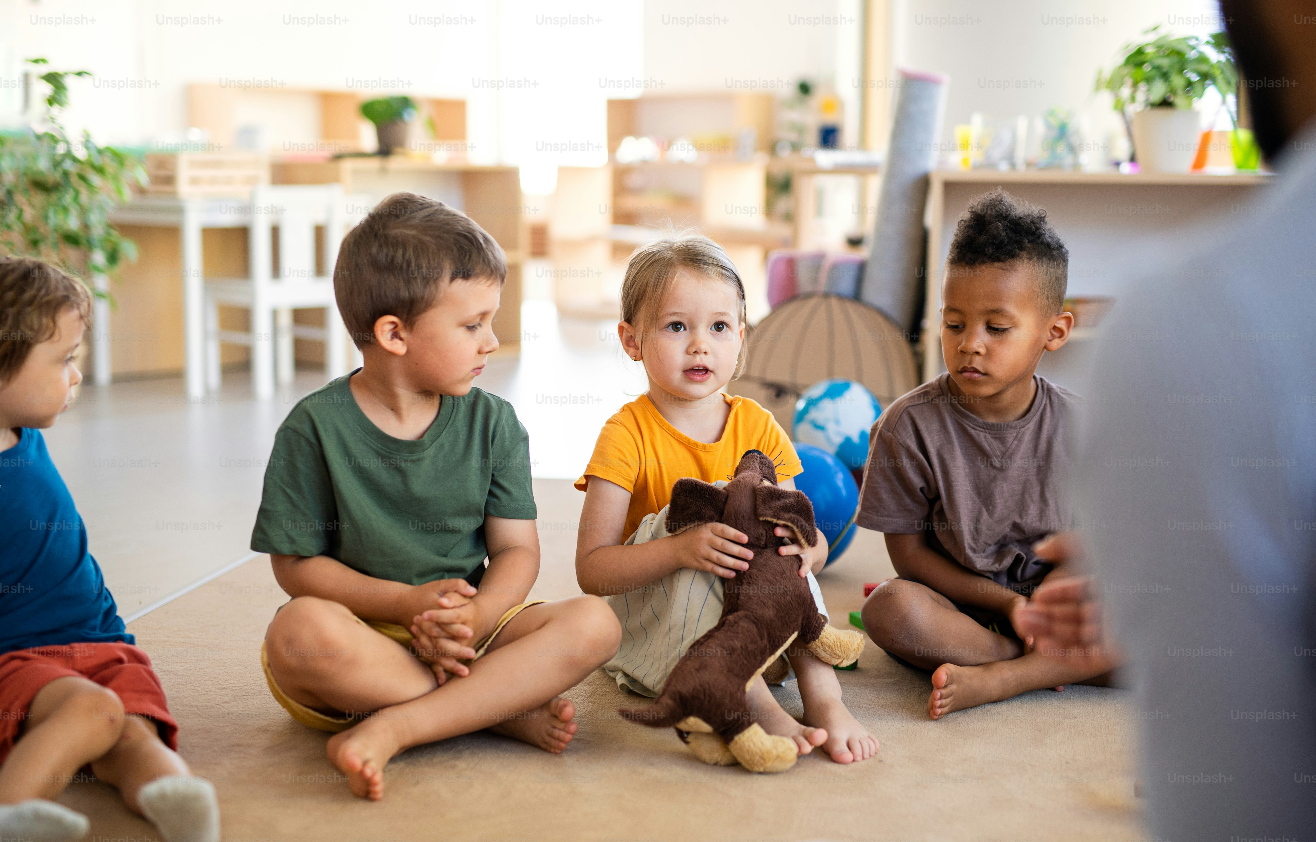 A group of small nursery school children playing indoors in classroom ...