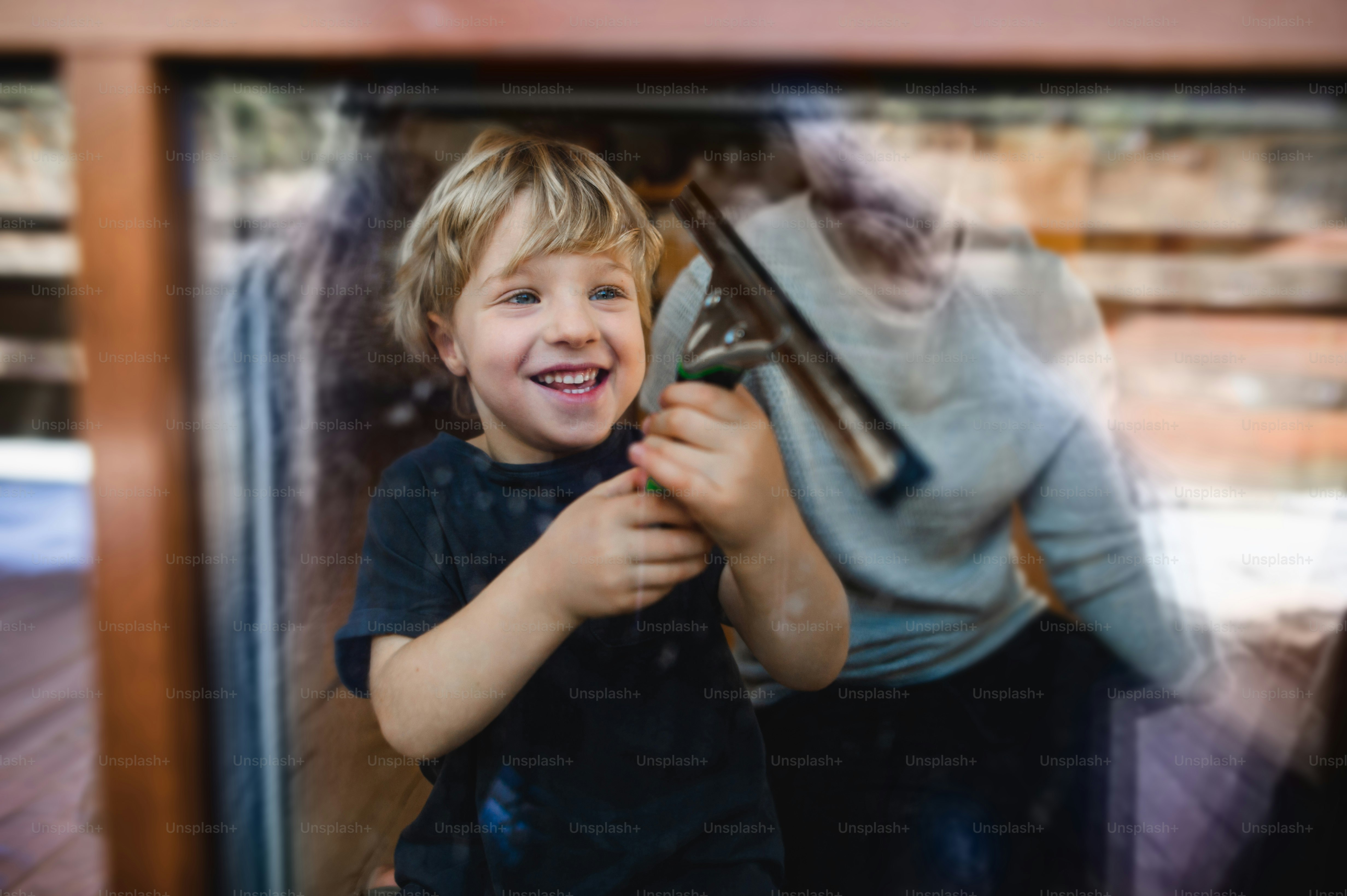 A Happy Boy With Unrecognizable Father Cleaning Windows At Home Daily