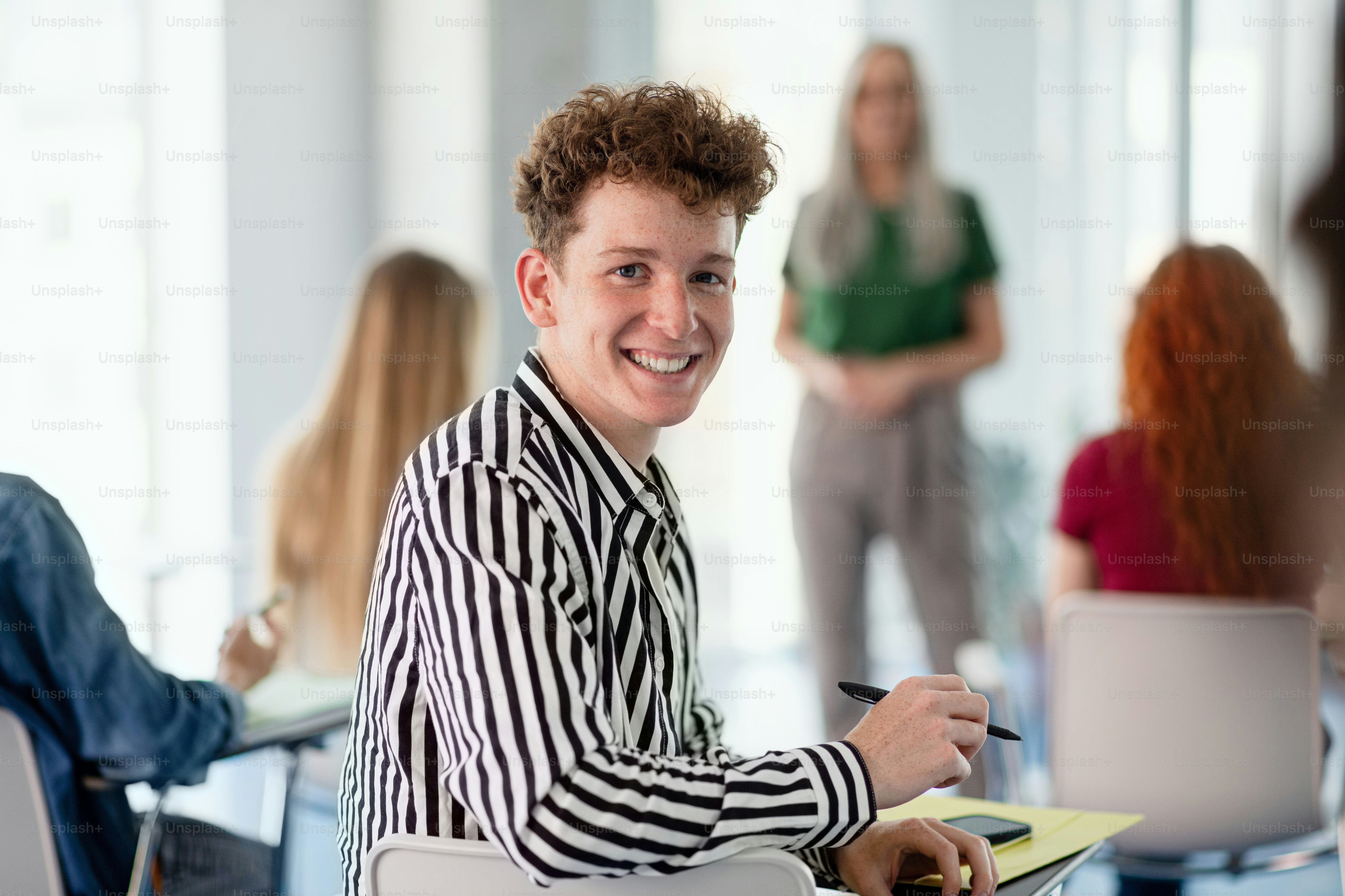 A portrait of young university student sitting in classroom indoors ...