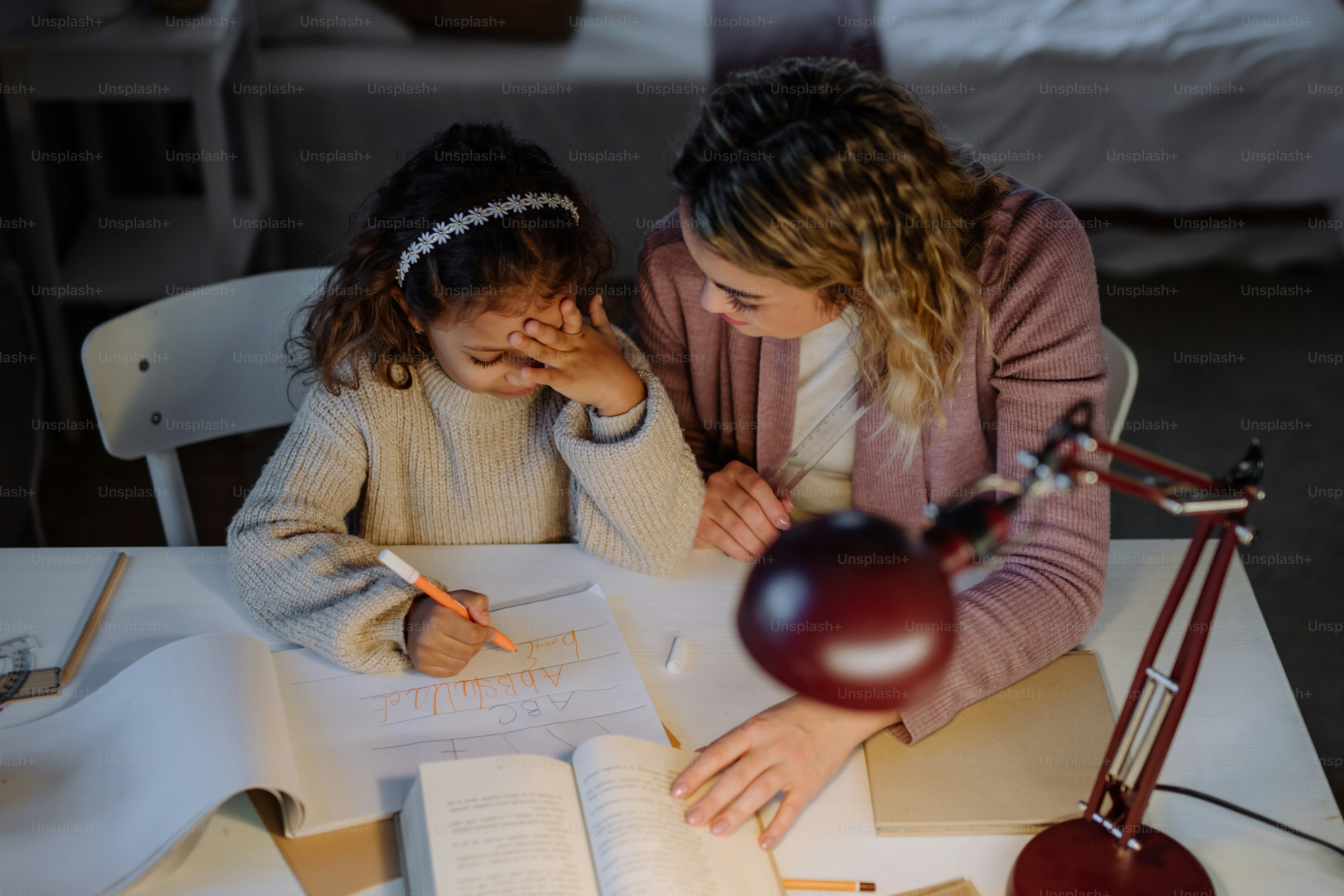 A high angle view of little girl doing homework with her mother in ...