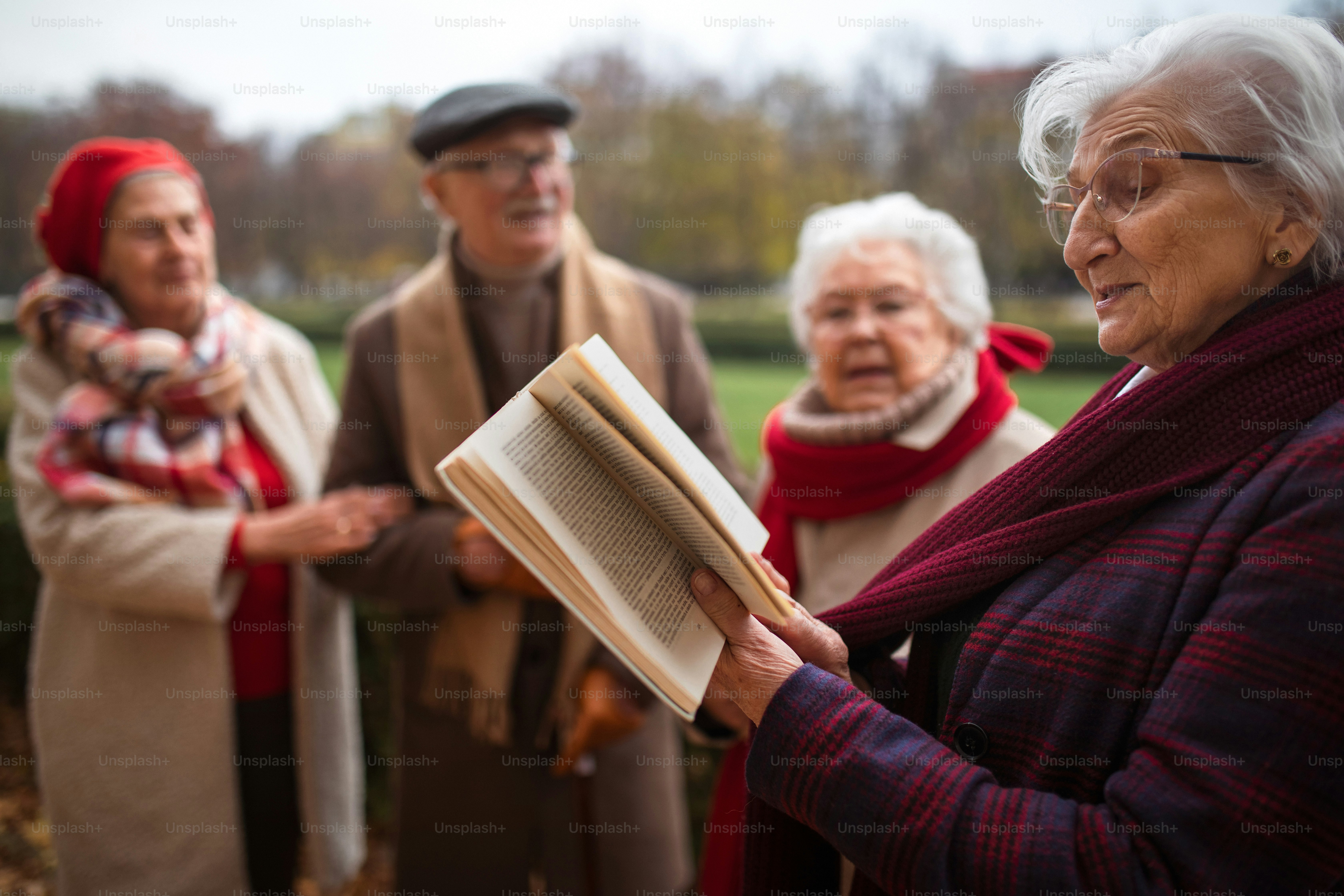 A group of happy senior friends with books on walk outdoors in park in ...