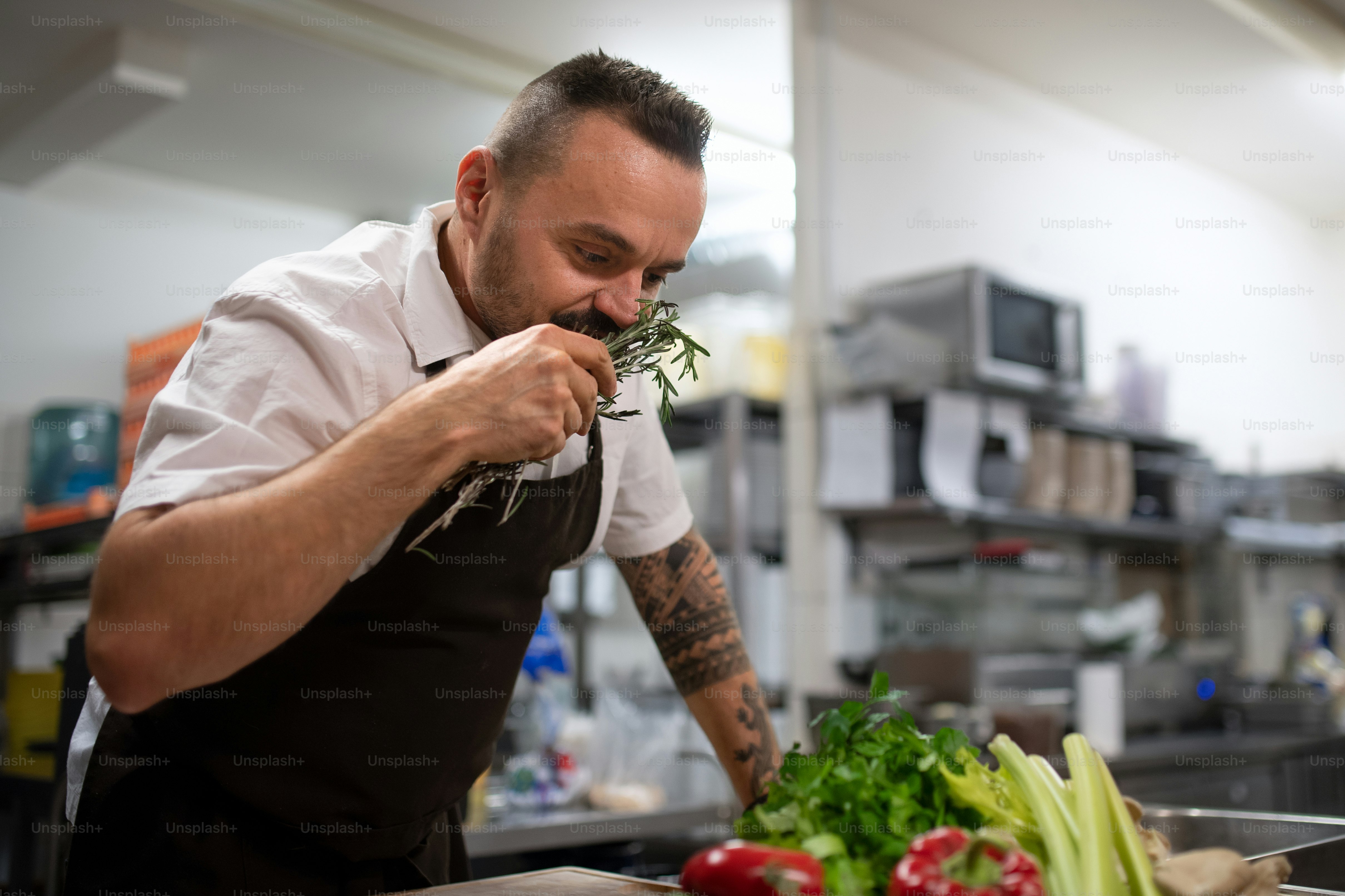A mature chef smelling herbs in commercial kitchen. photo – Creative ...