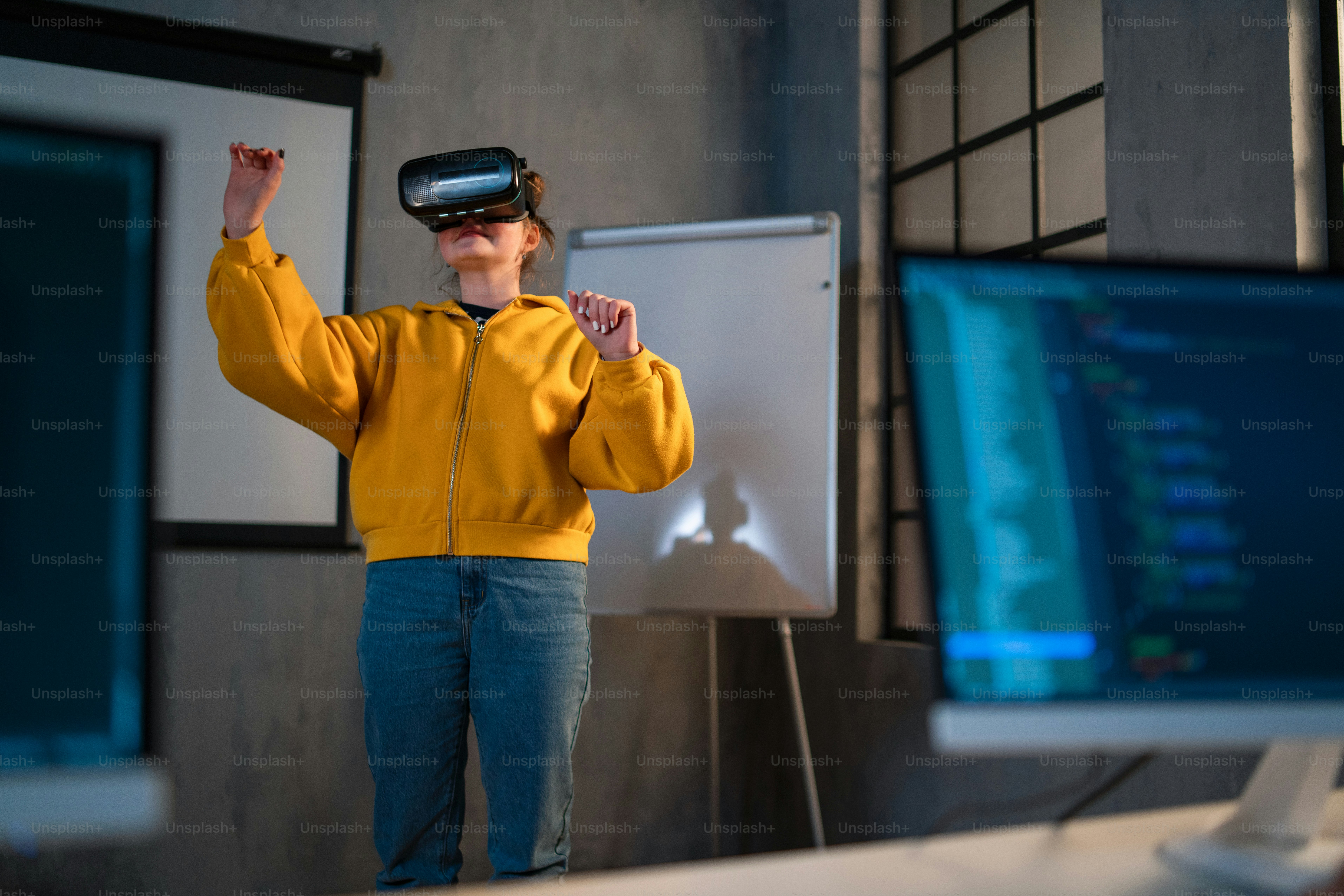 A schoolgirl wearing virtual reality goggles at school in computer ...
