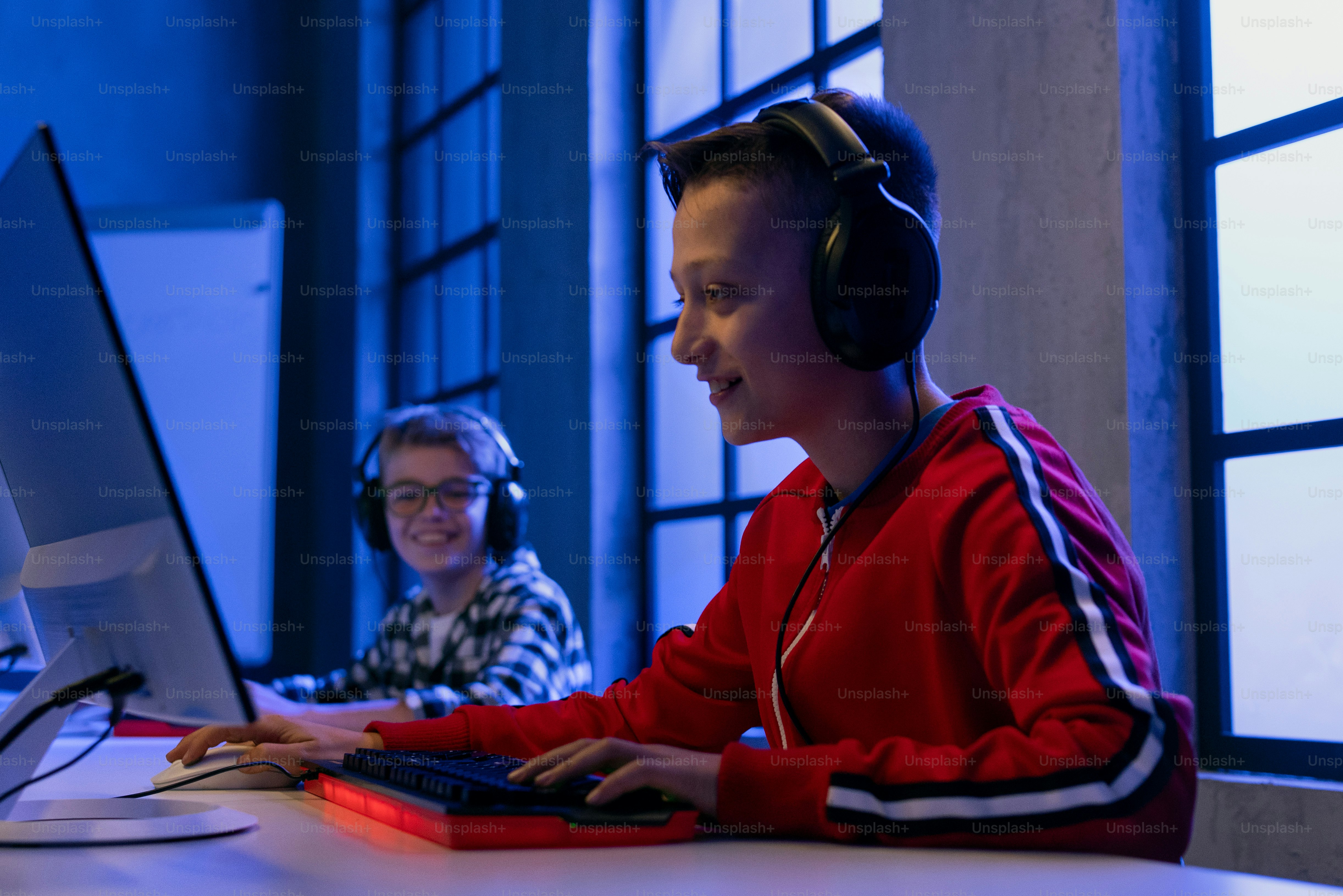 Young gamer boys with headphones playing a computer video game. photo ...
