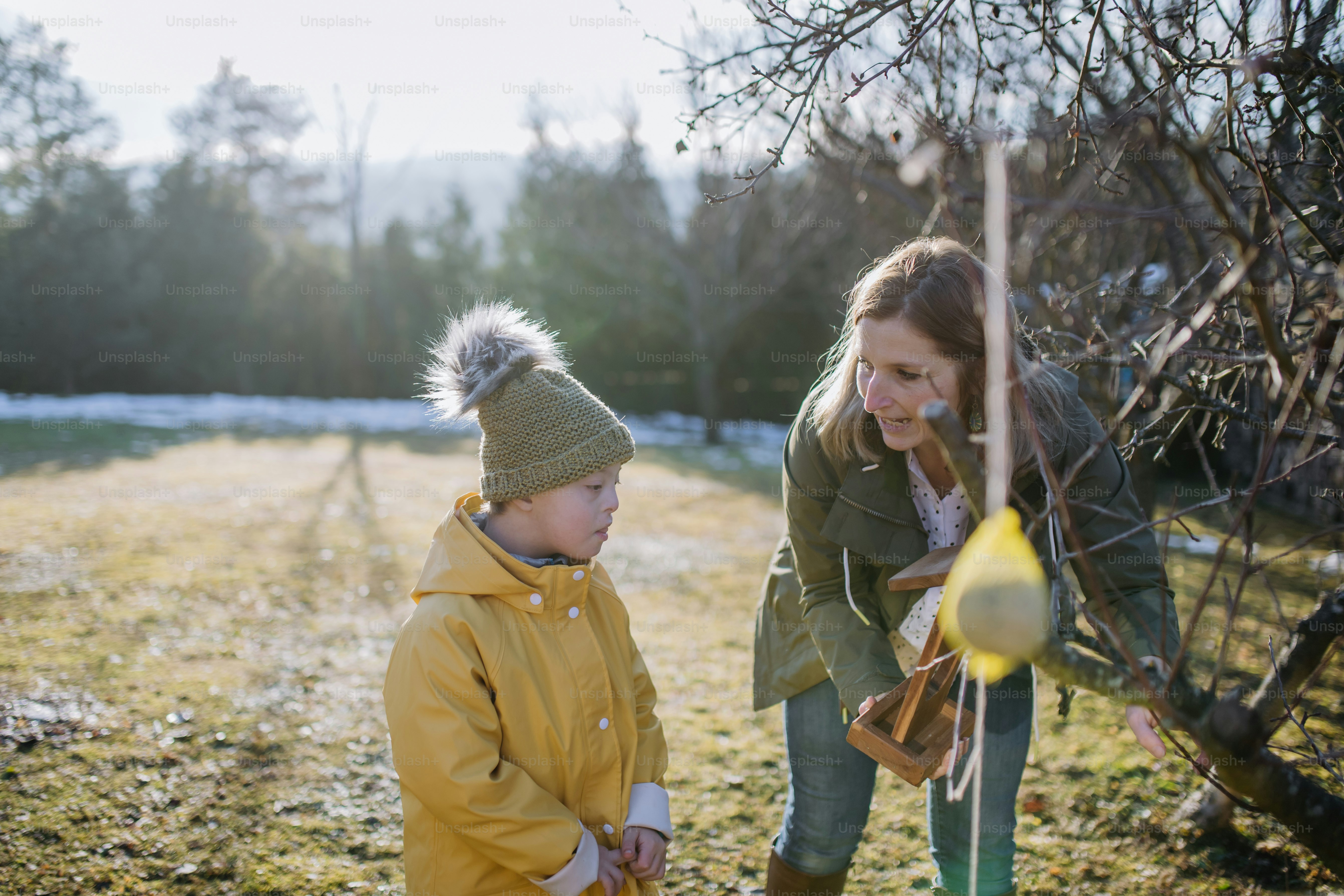 A boy with Down syndrome feeding birds in garden in winter with his ...