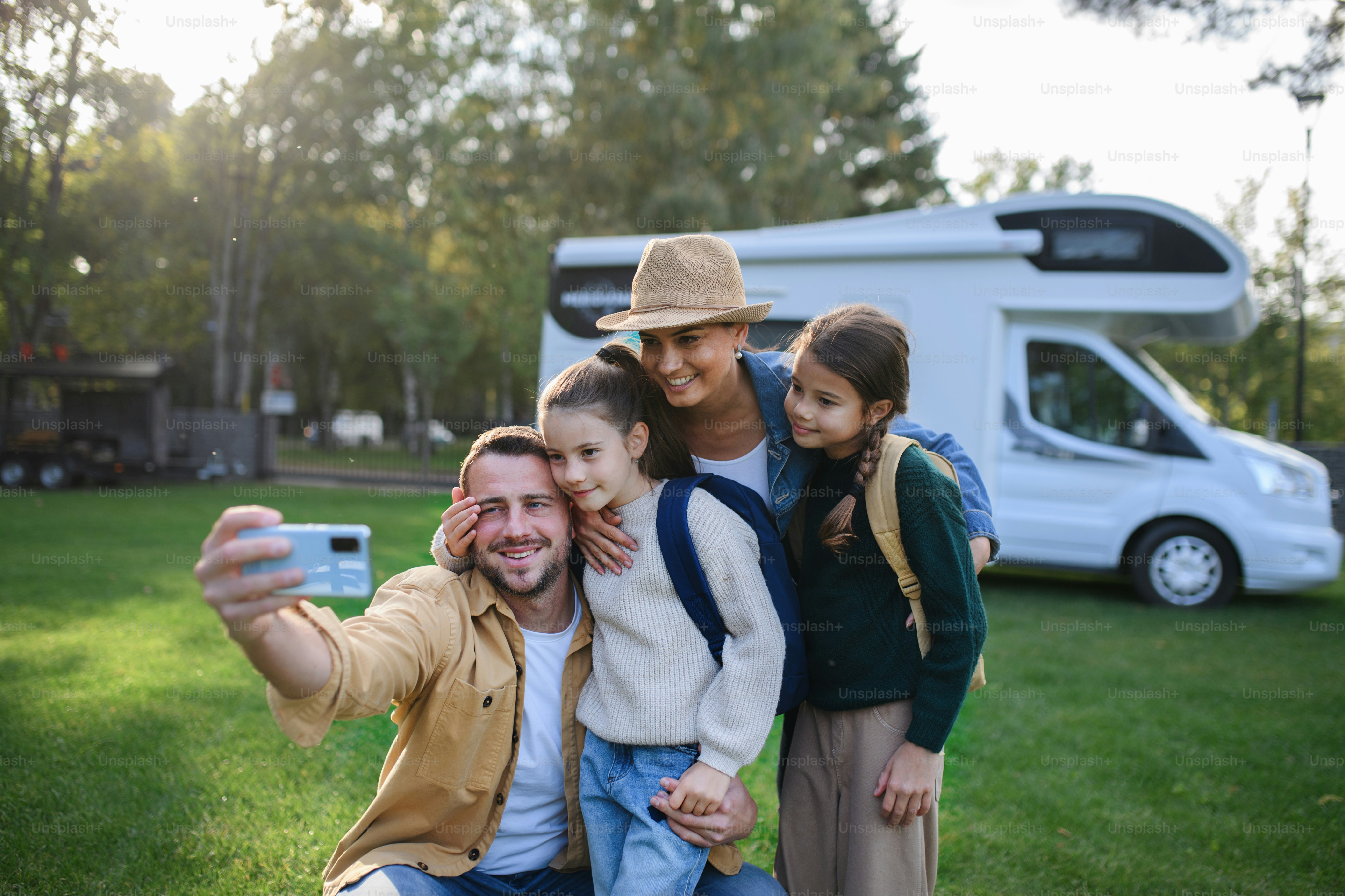 A happy young family with two children ltaking selfie with caravan at ...