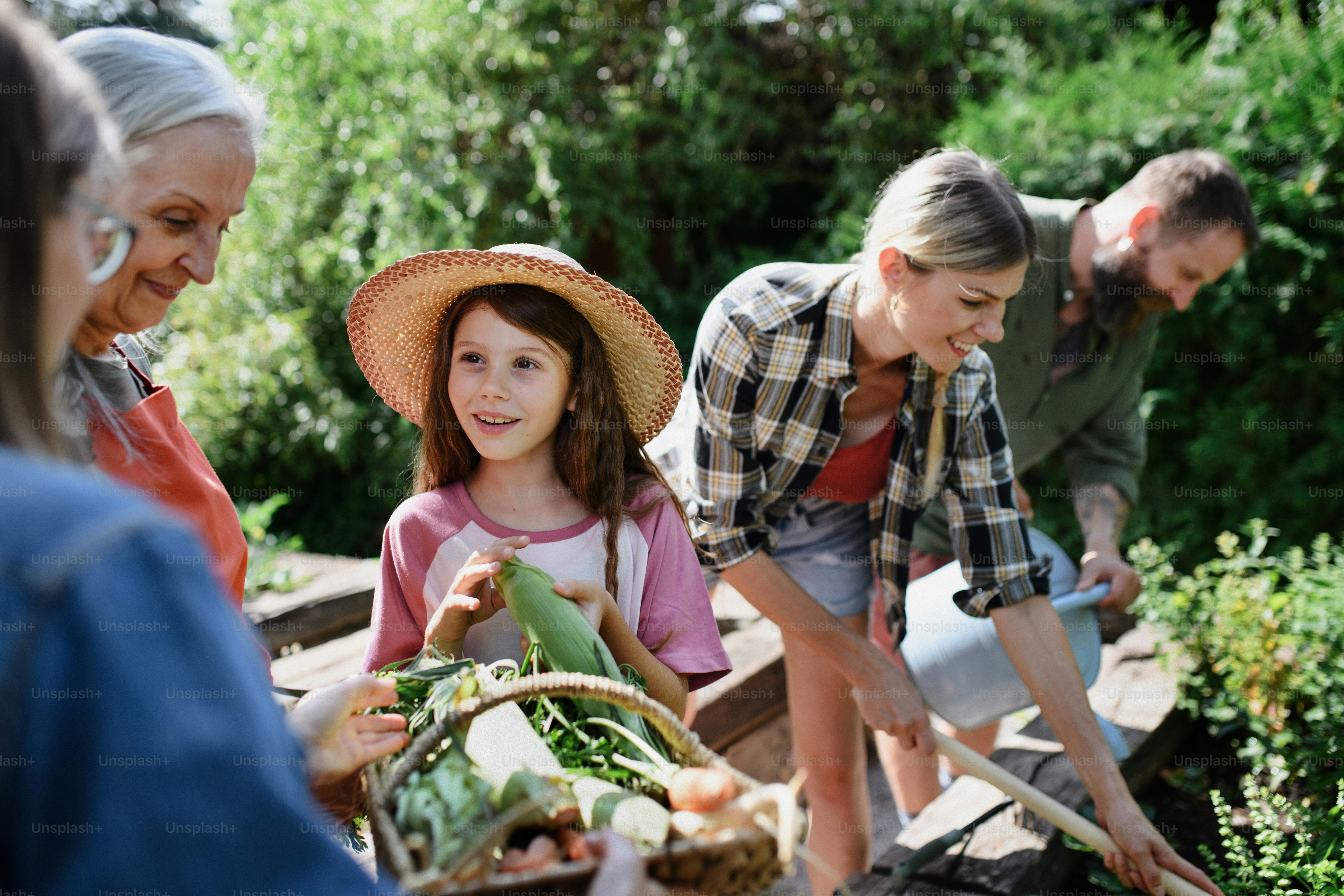 A happy farmers family working with garden tools outdoors at community ...