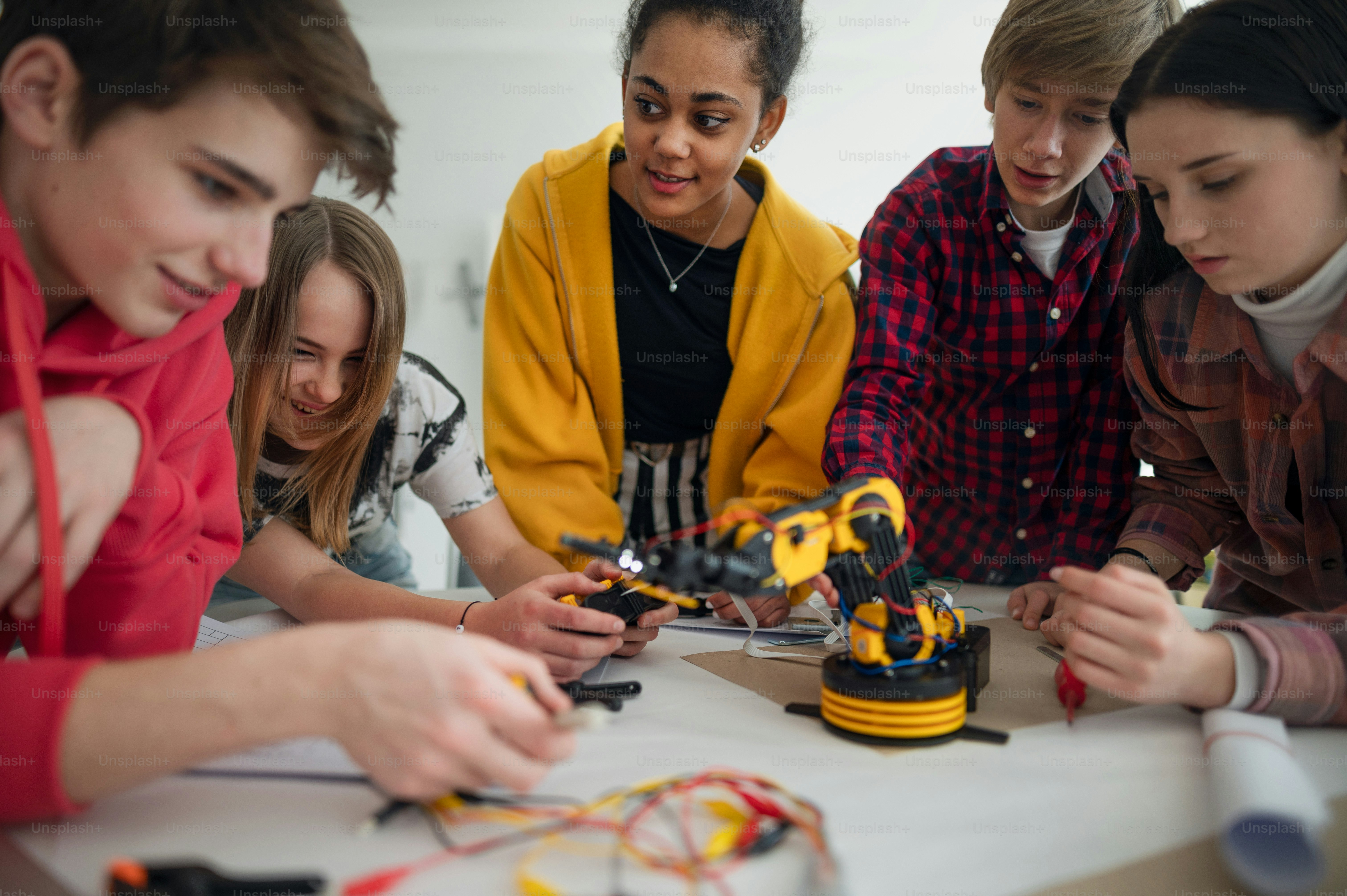 A group of kids with young science teacher programming electric toys ...