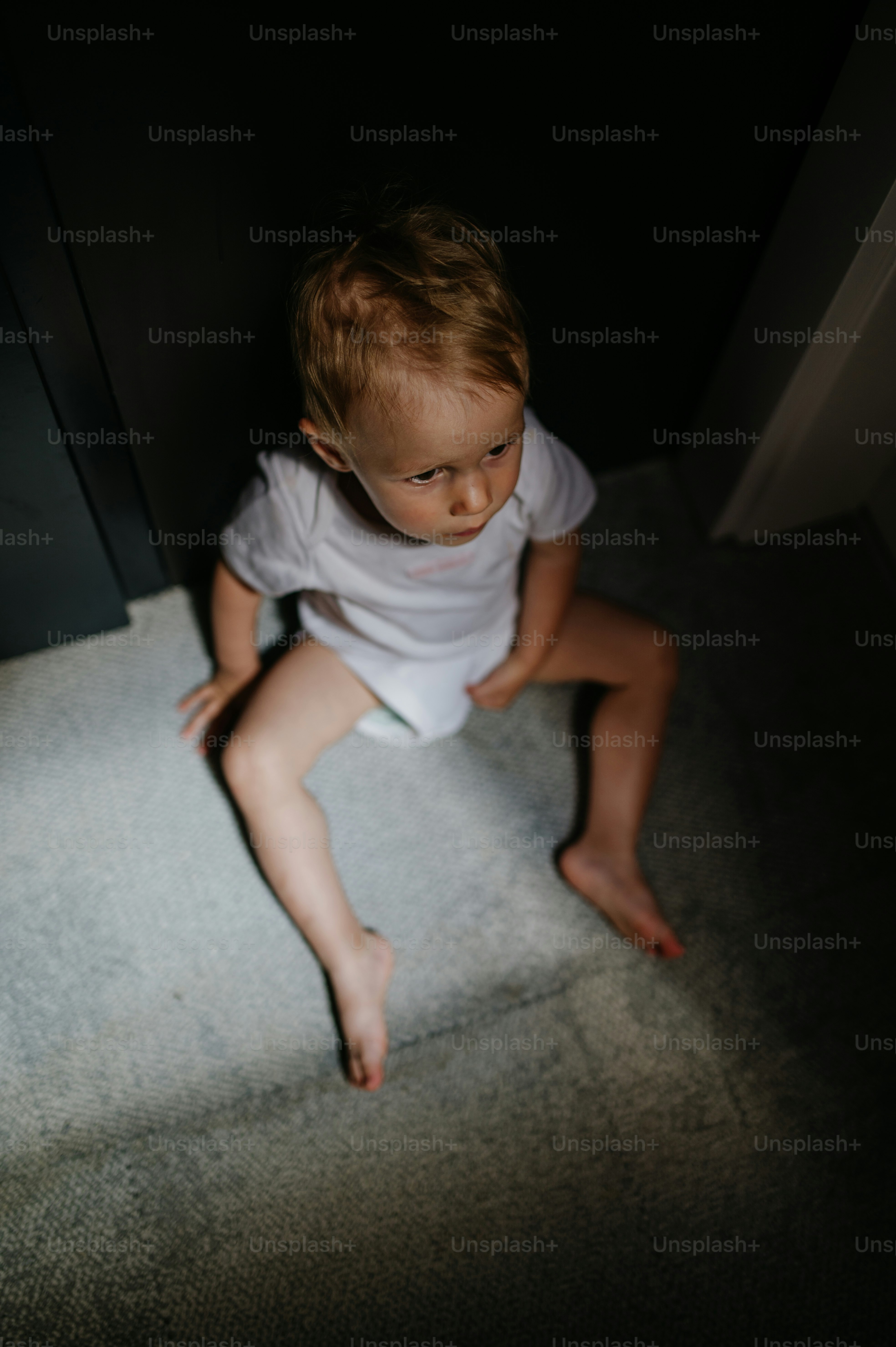 A dark high angle view portrait of sad anonymous little baby girl ...