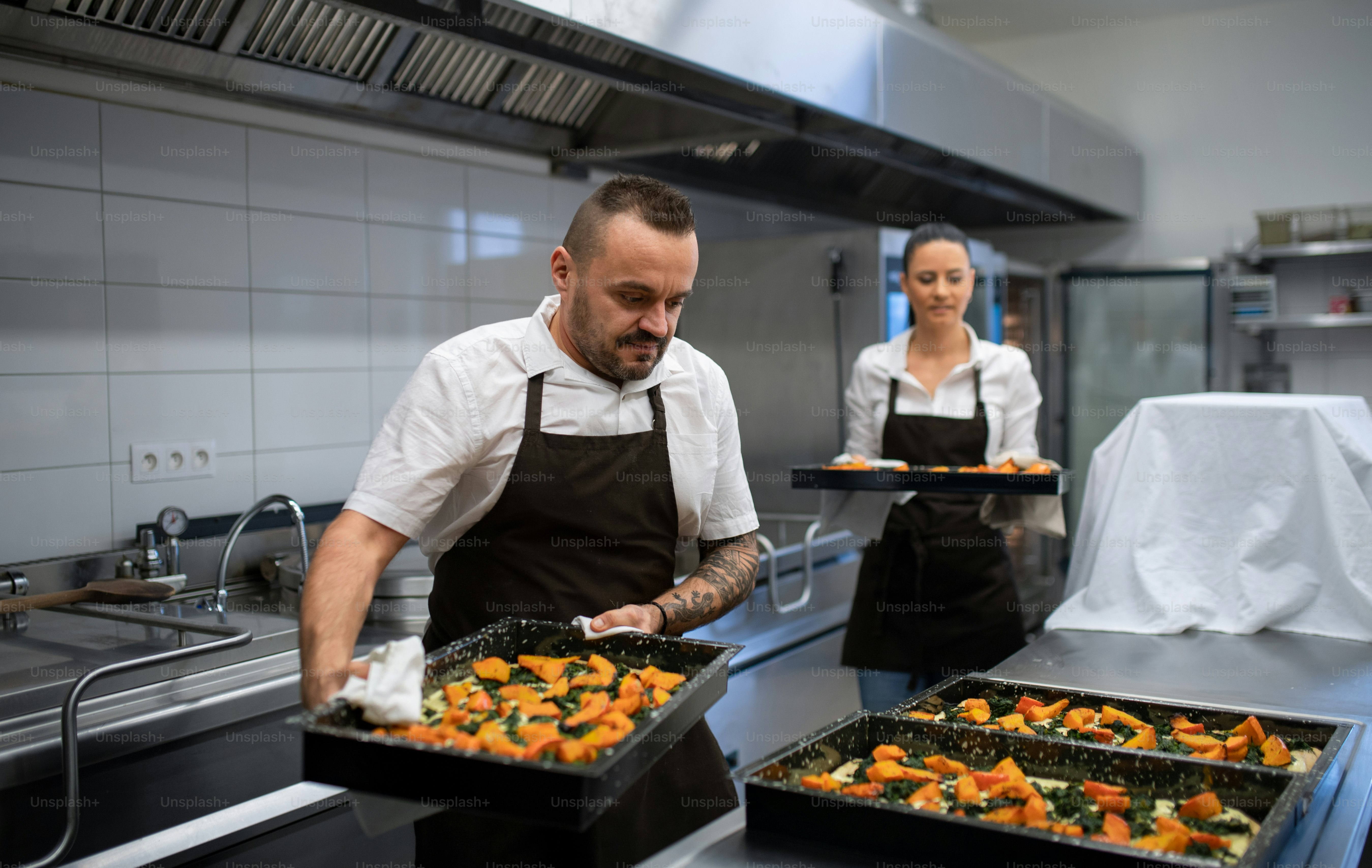 A chef and cook working on their dishes indoors in restaurant kitchen ...