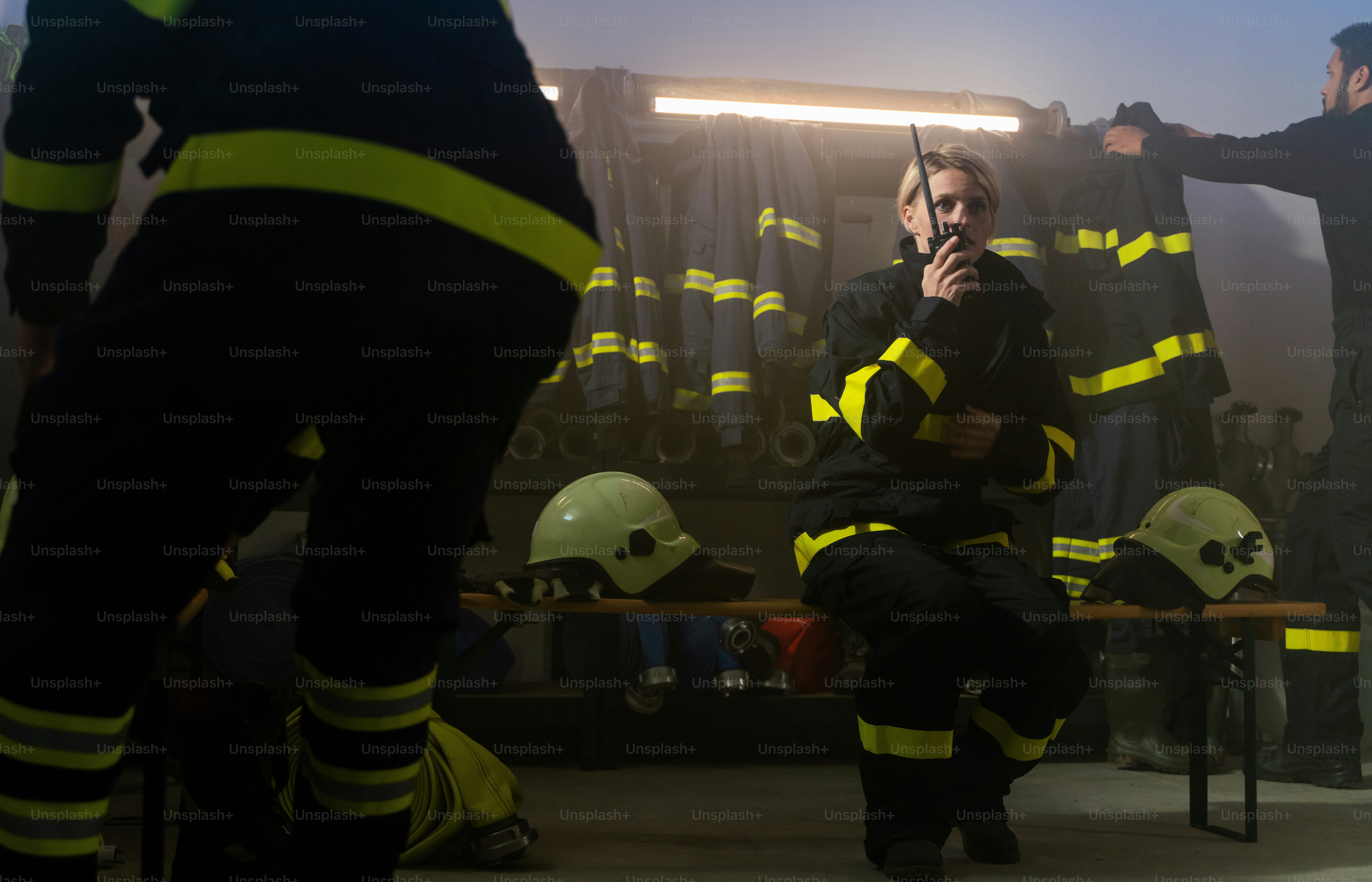 Busy firefighters men and woman getting ready for an action indoors in ...