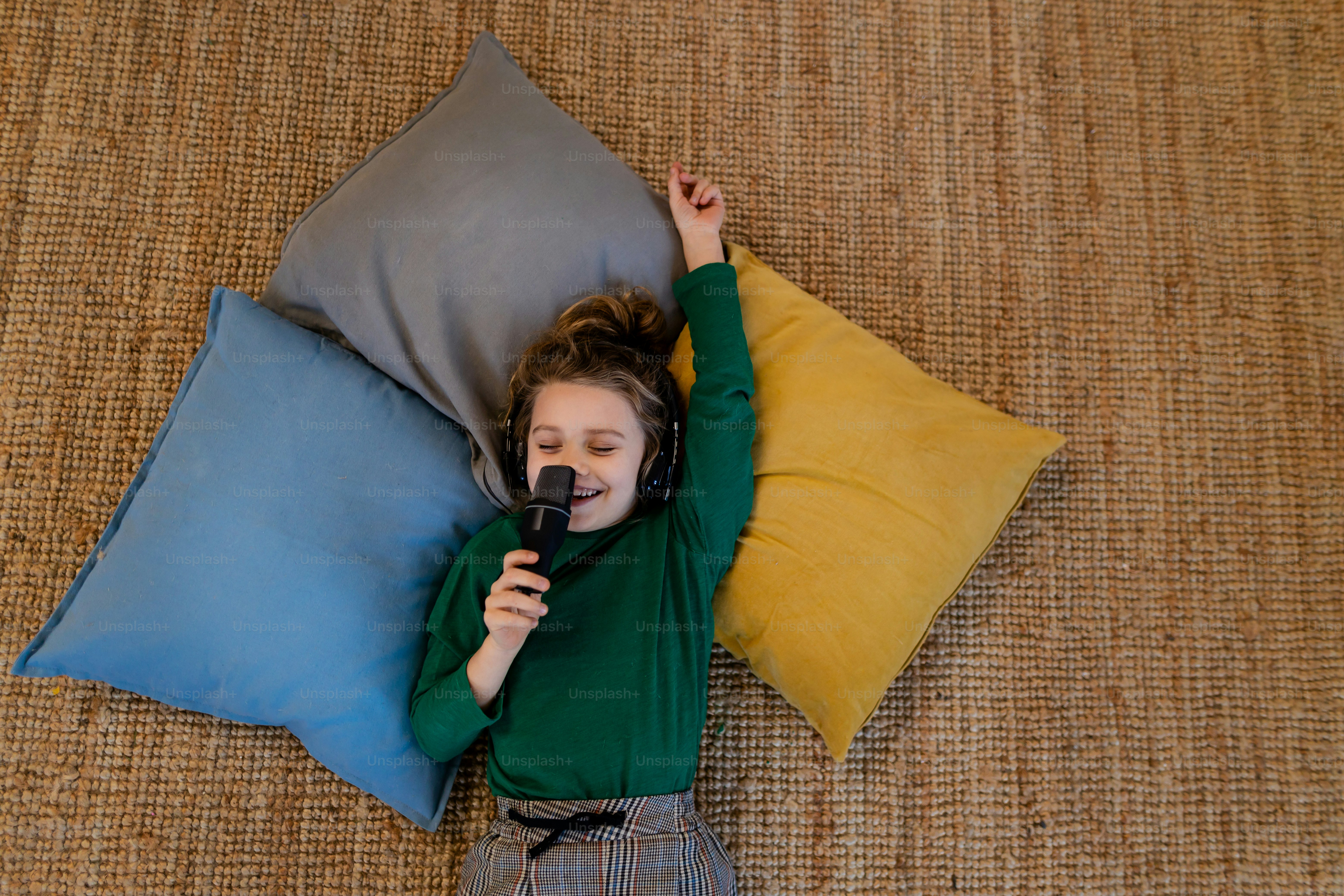 A little girl lying on the floor on cushions listening music,singing ...