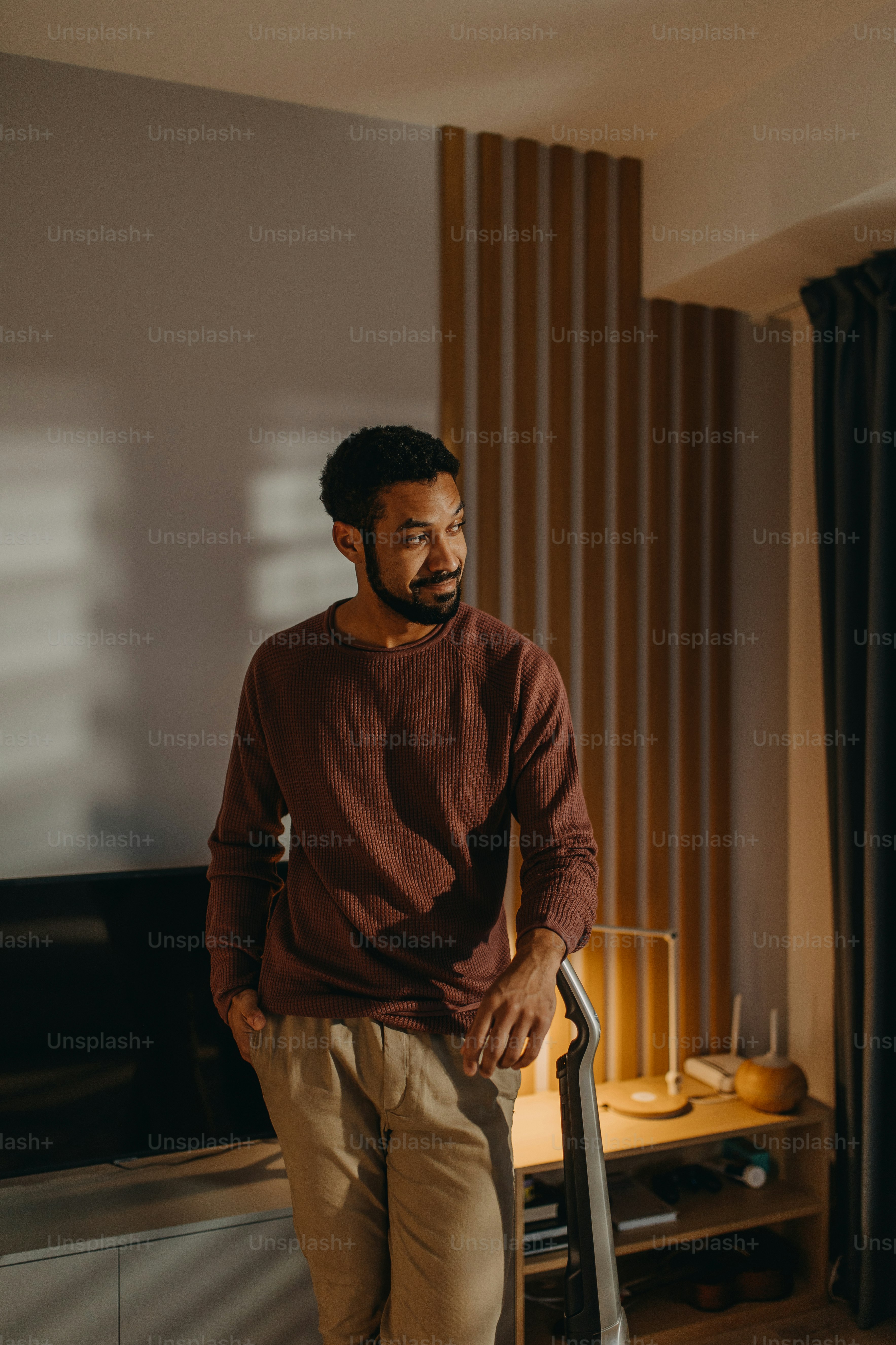 A young man hoovering carpet with vacuum cleaner in living room photo ...