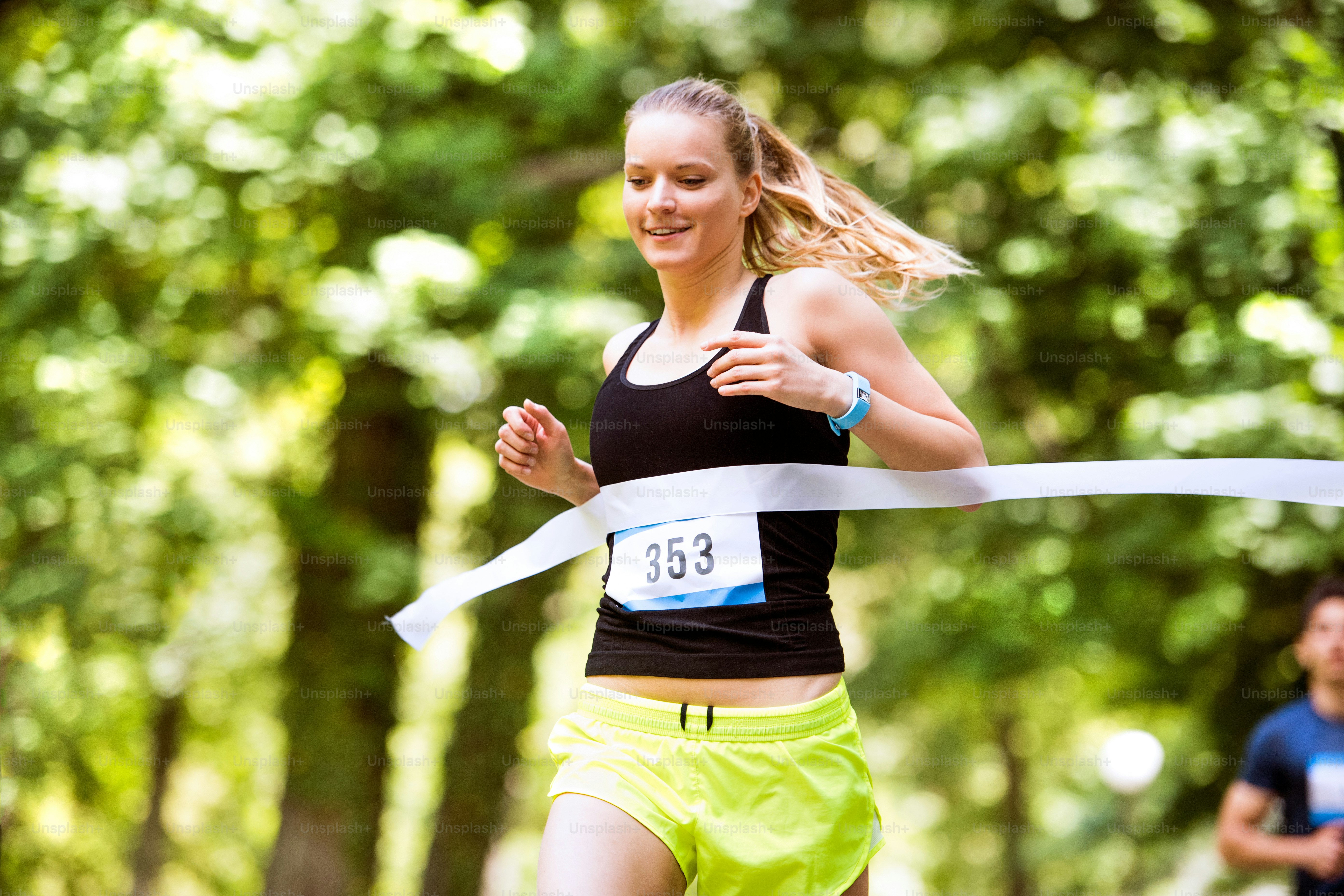 Foto Hermosa joven corriendo la carrera cruzando la línea de meta ...