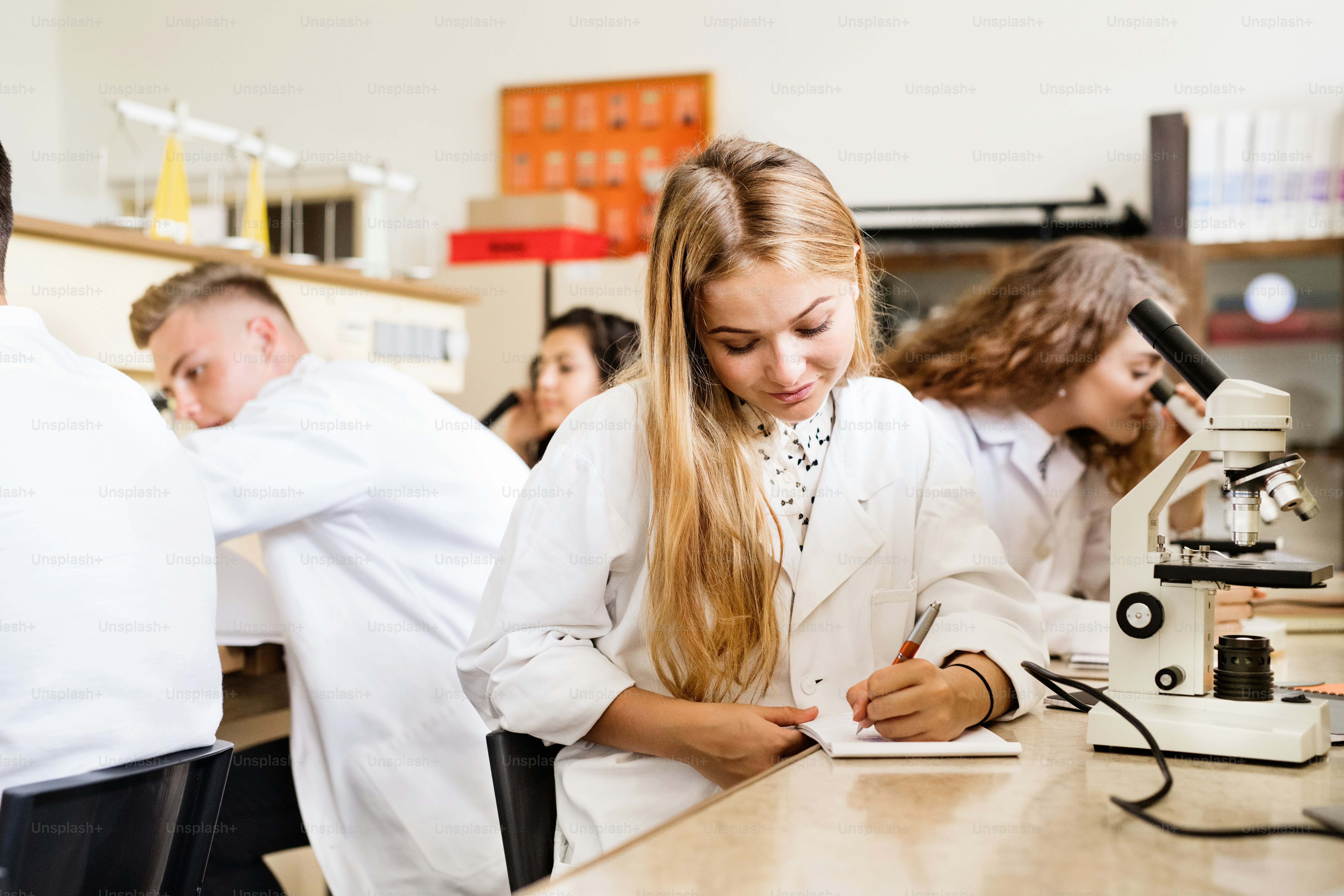 Group of high school student with microscopes in laboratory during ...