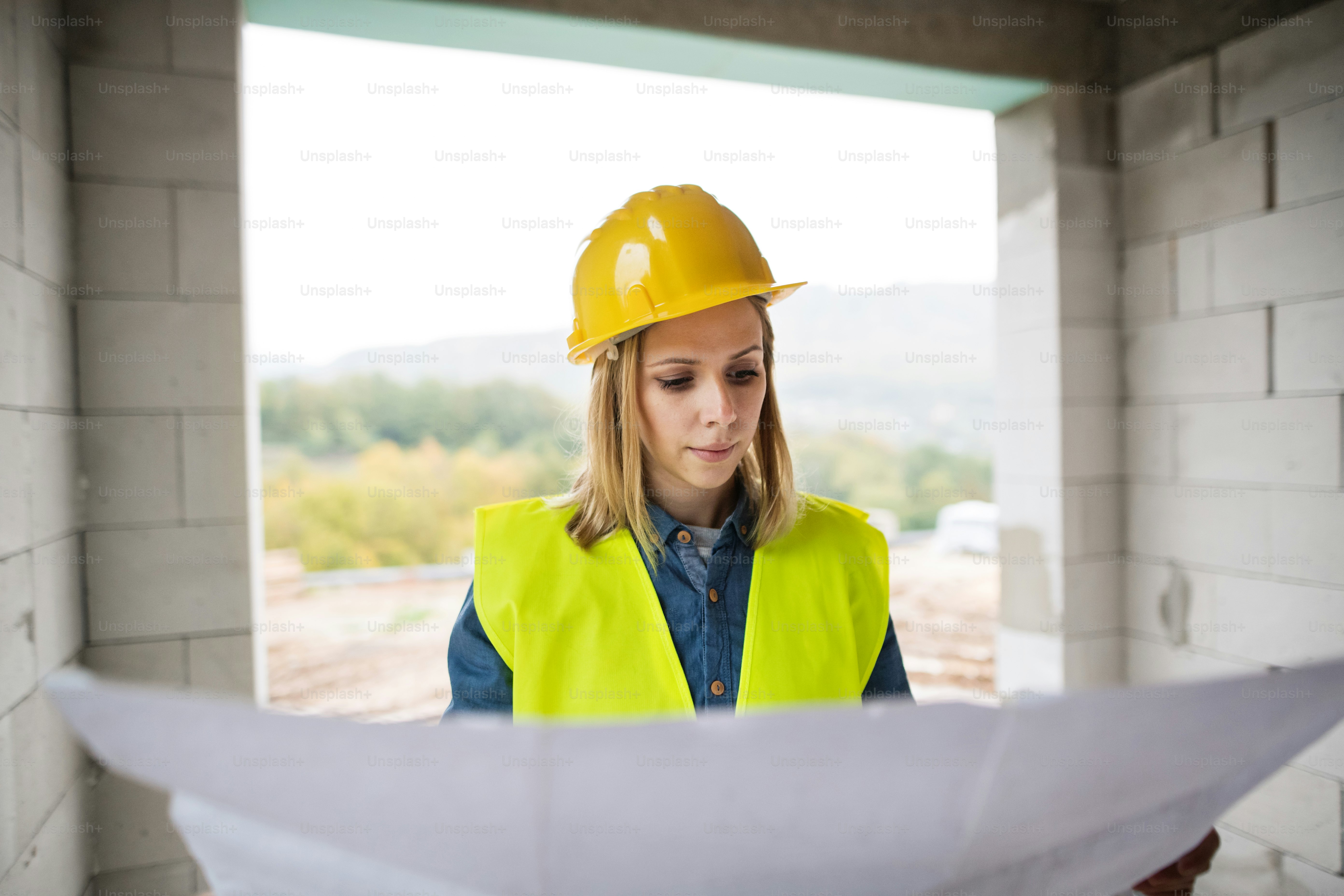 Female worker on the building site. Beautiful young woman holding ...