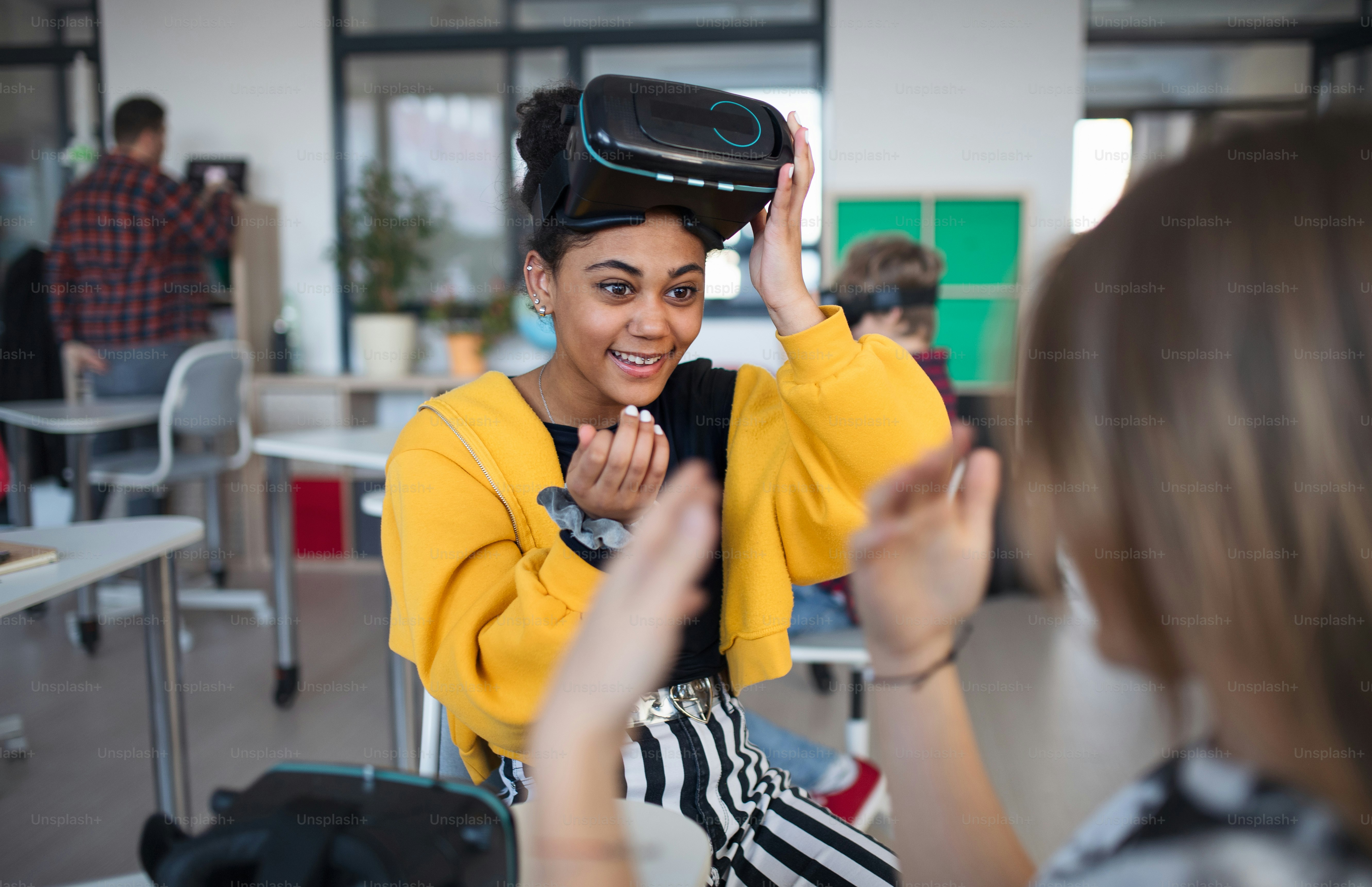 A happy student wearing virtual reality goggles at school in computer ...
