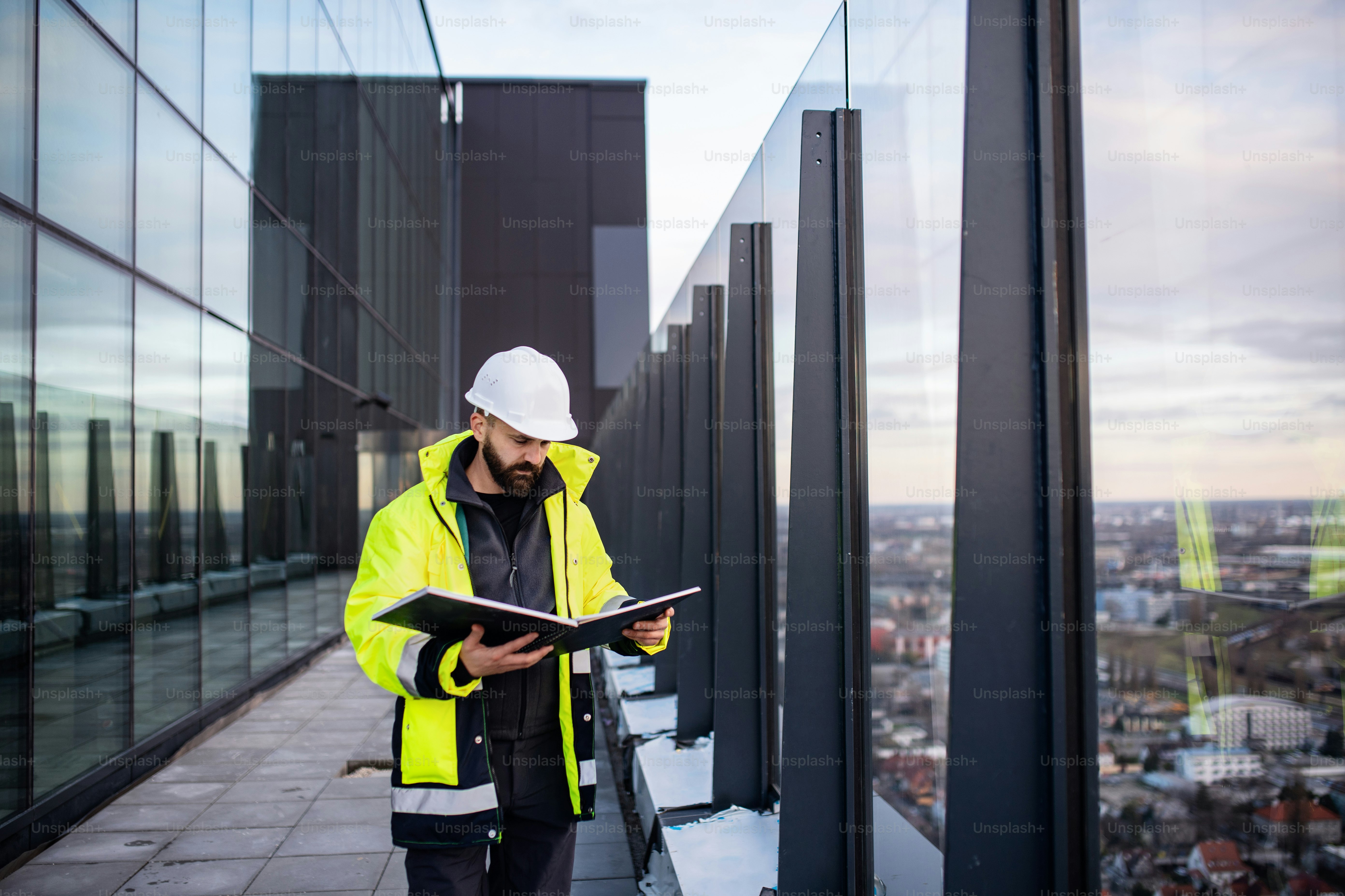 Mature man engineer standing on construction site, holding tablet with ...