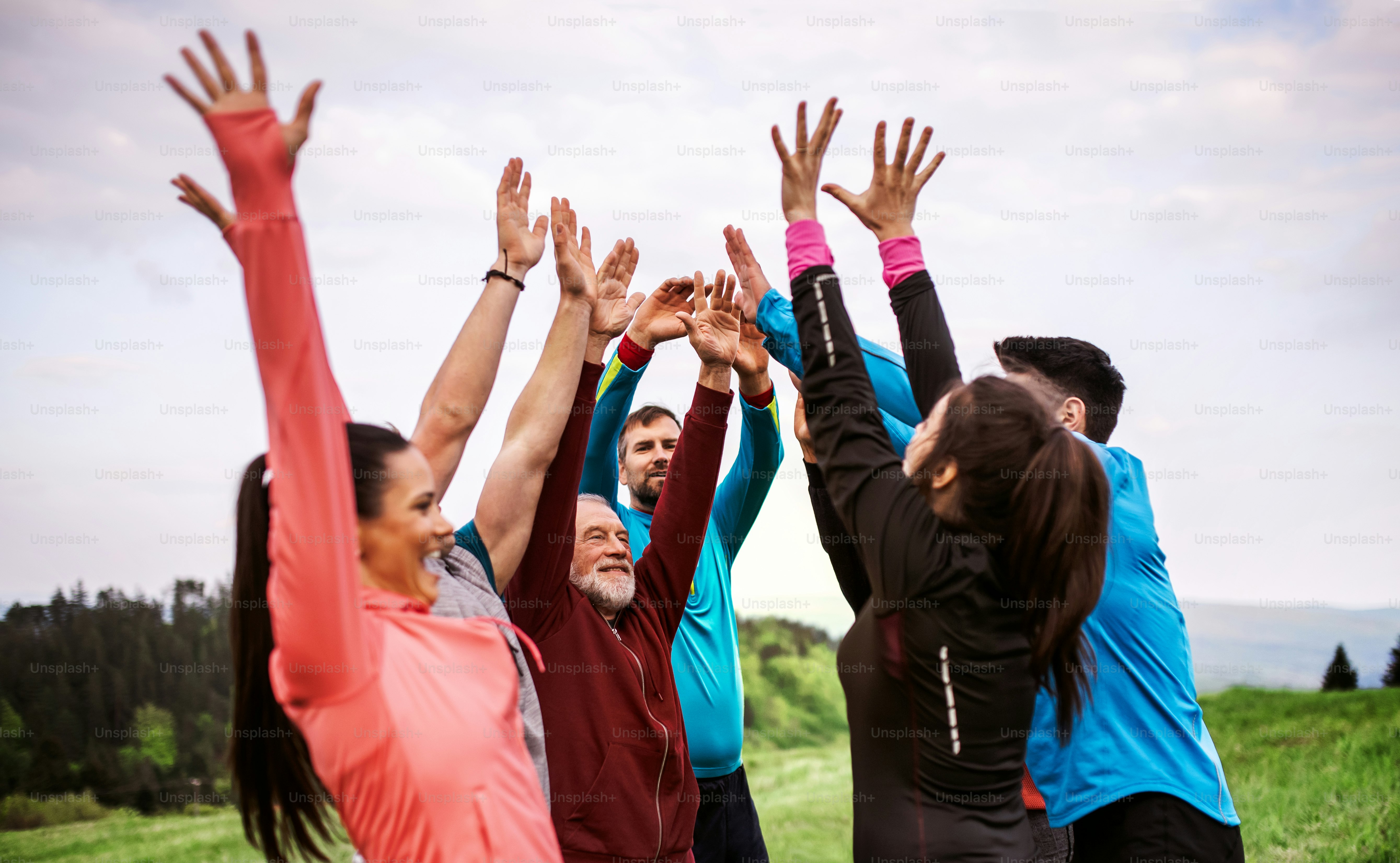 A large group of fit and active people jumping after doing exercise in ...