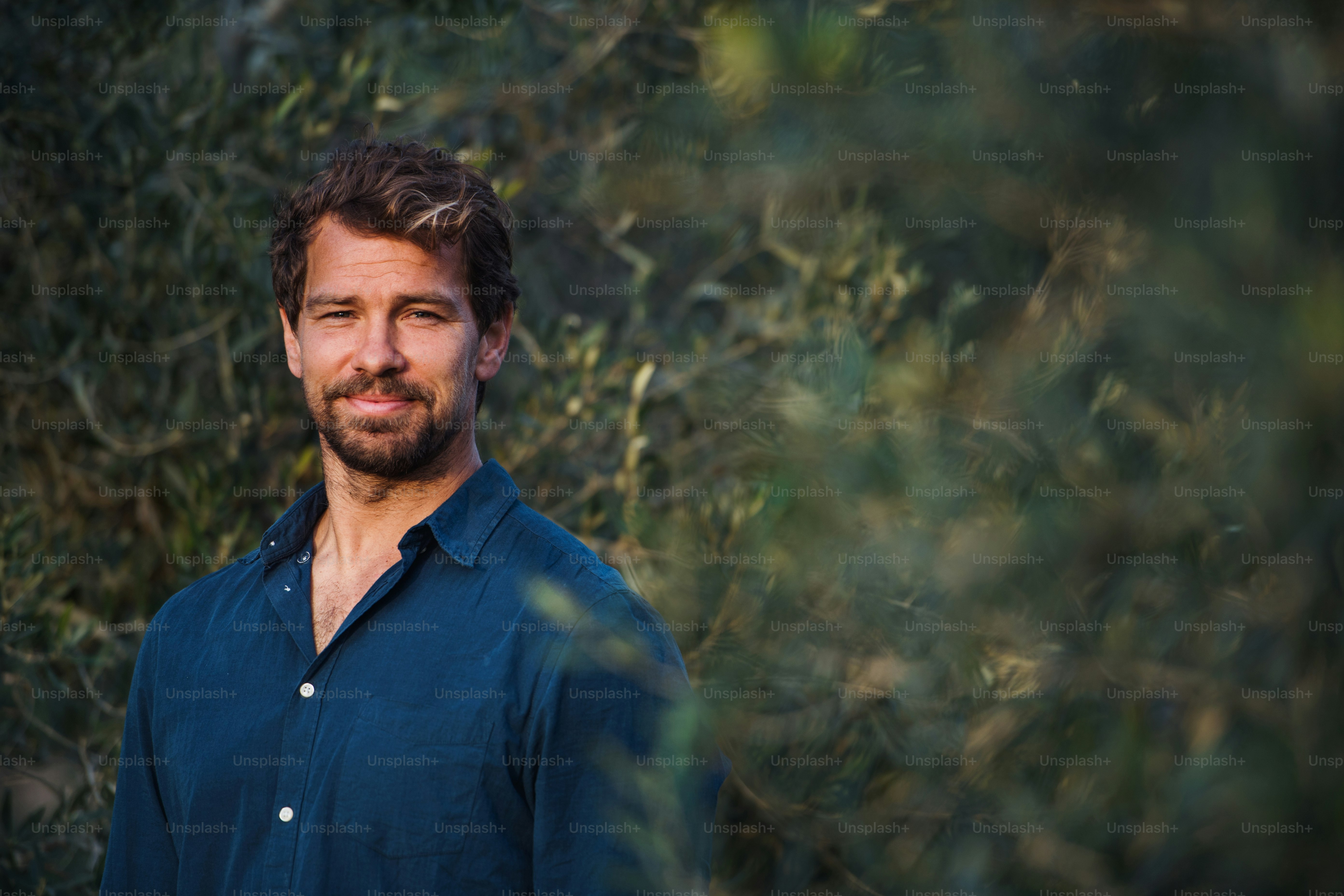 Handsome bearded man standing outdoors by olive tree. Copy space. photo ...