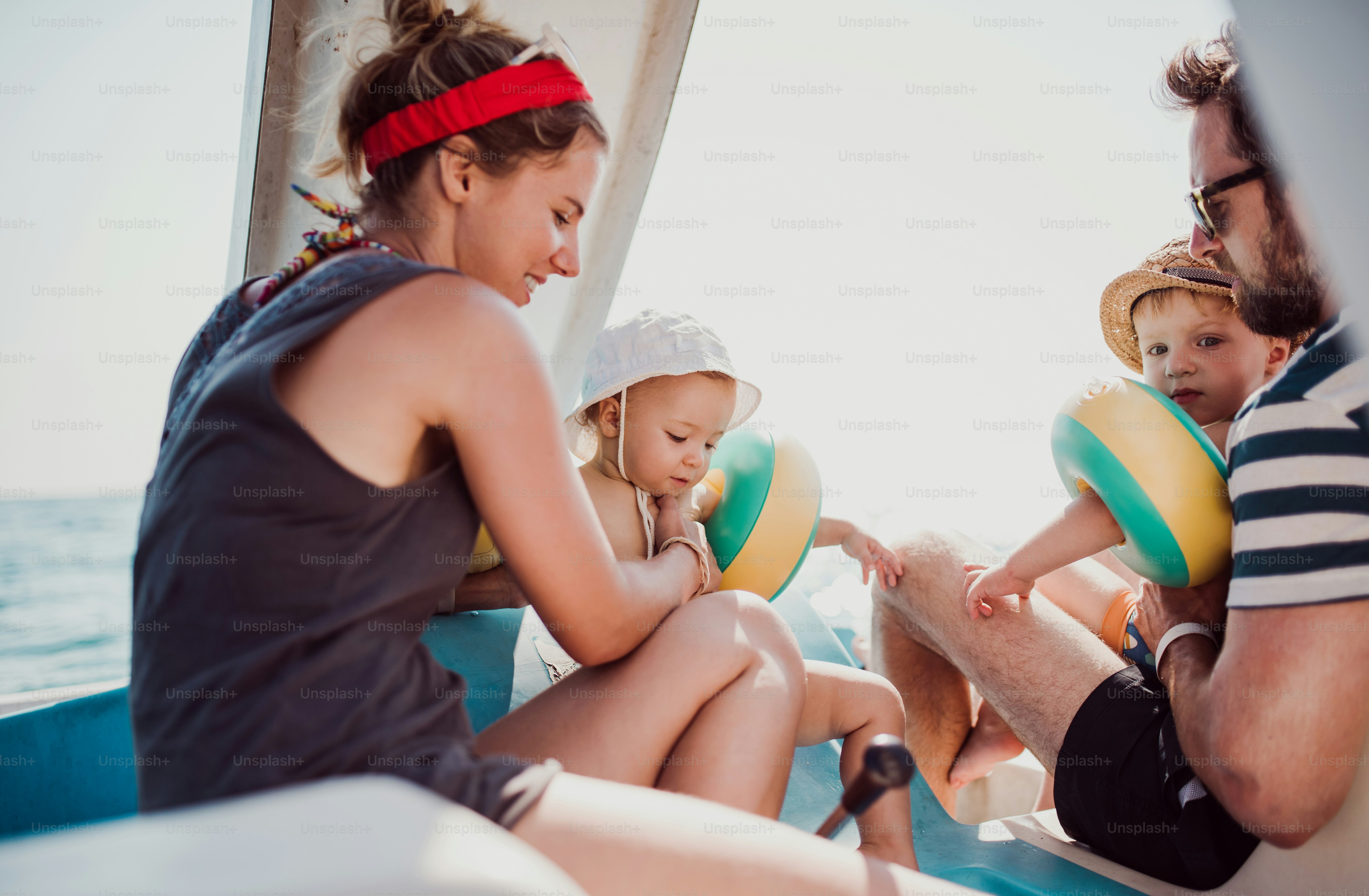 Happy parents with two small toddler children sitting on boat on summer ...