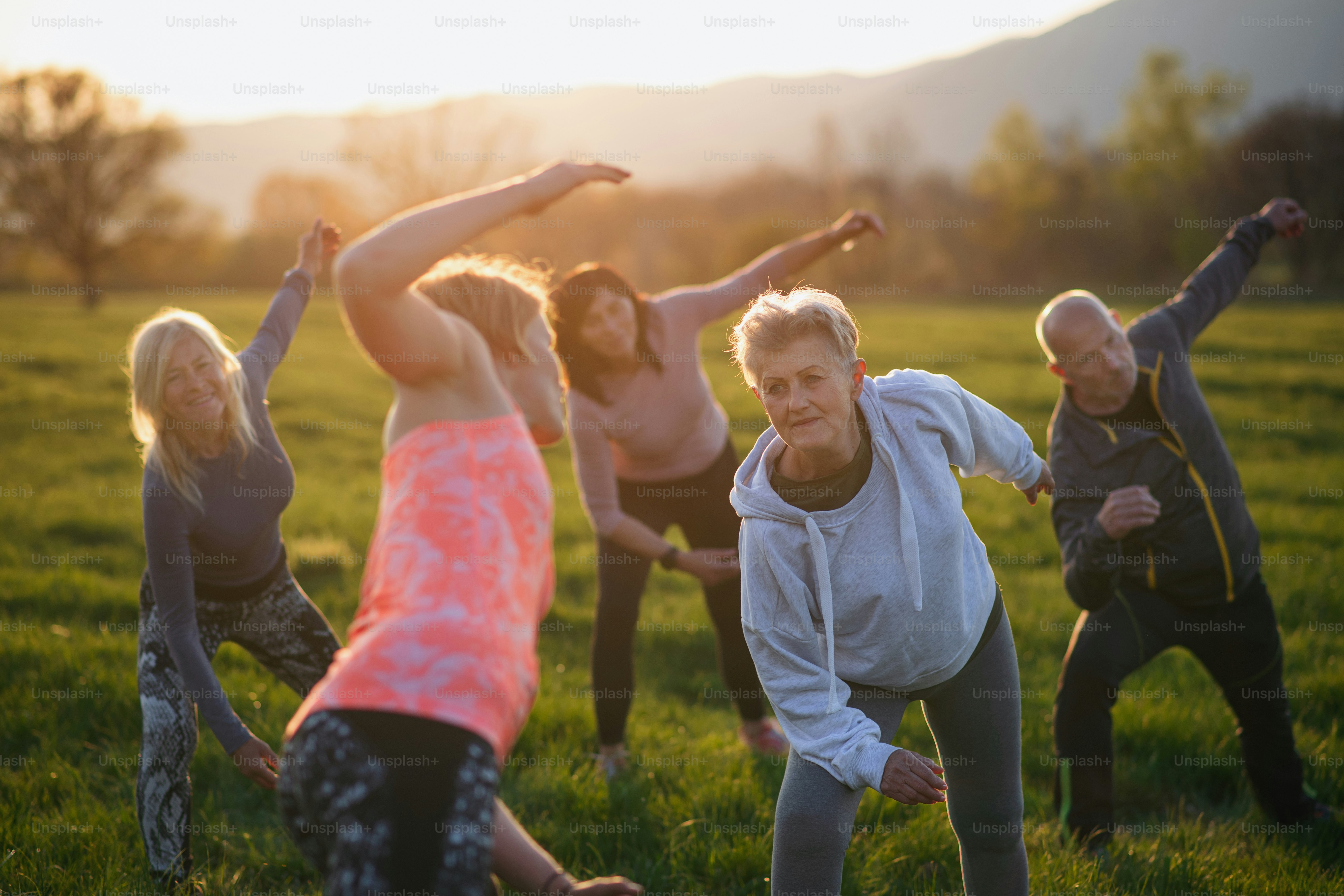 A group of seniors with sport instructor doing exercise outdoors in ...