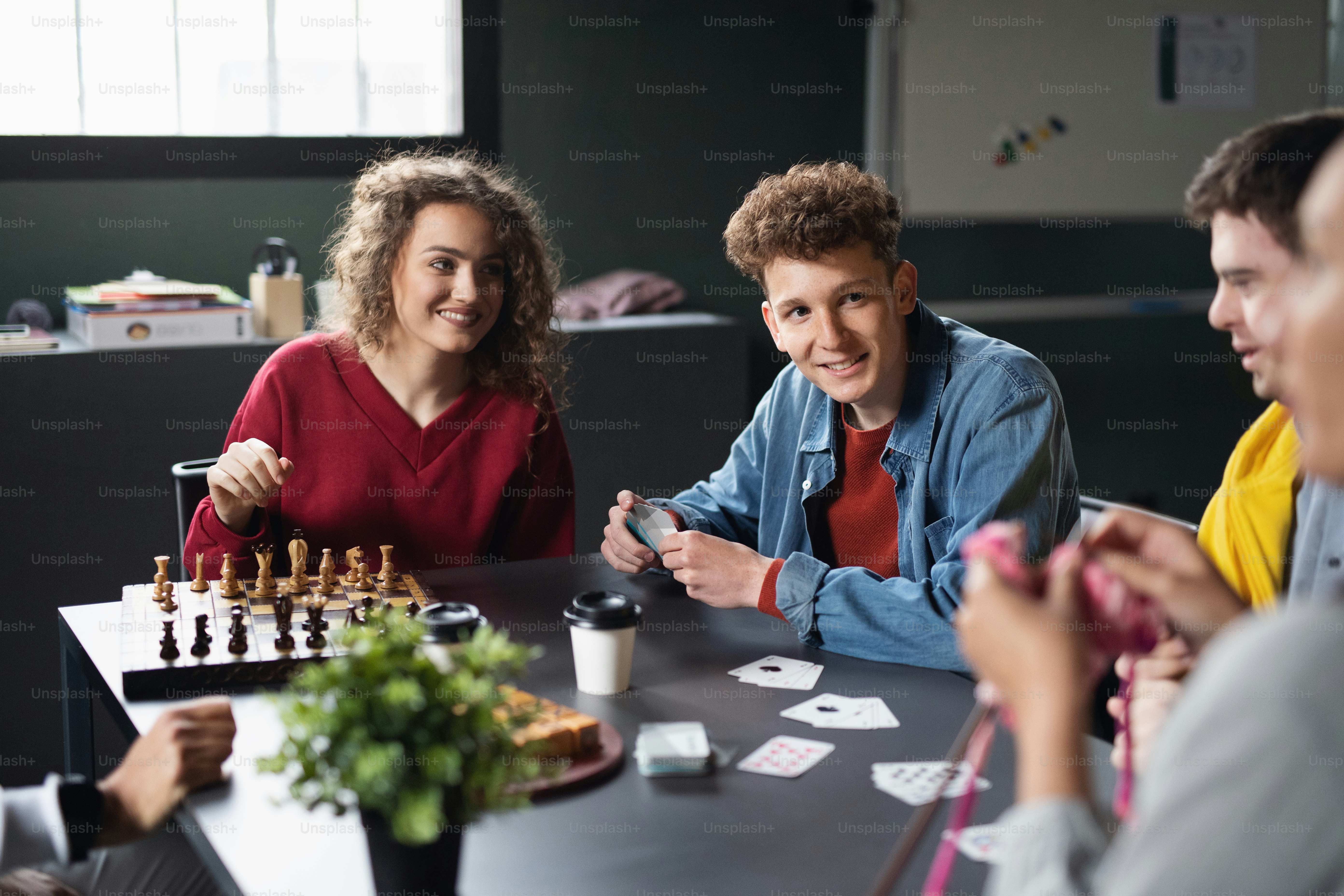 Group of happy people playing cards and board games in community center ...