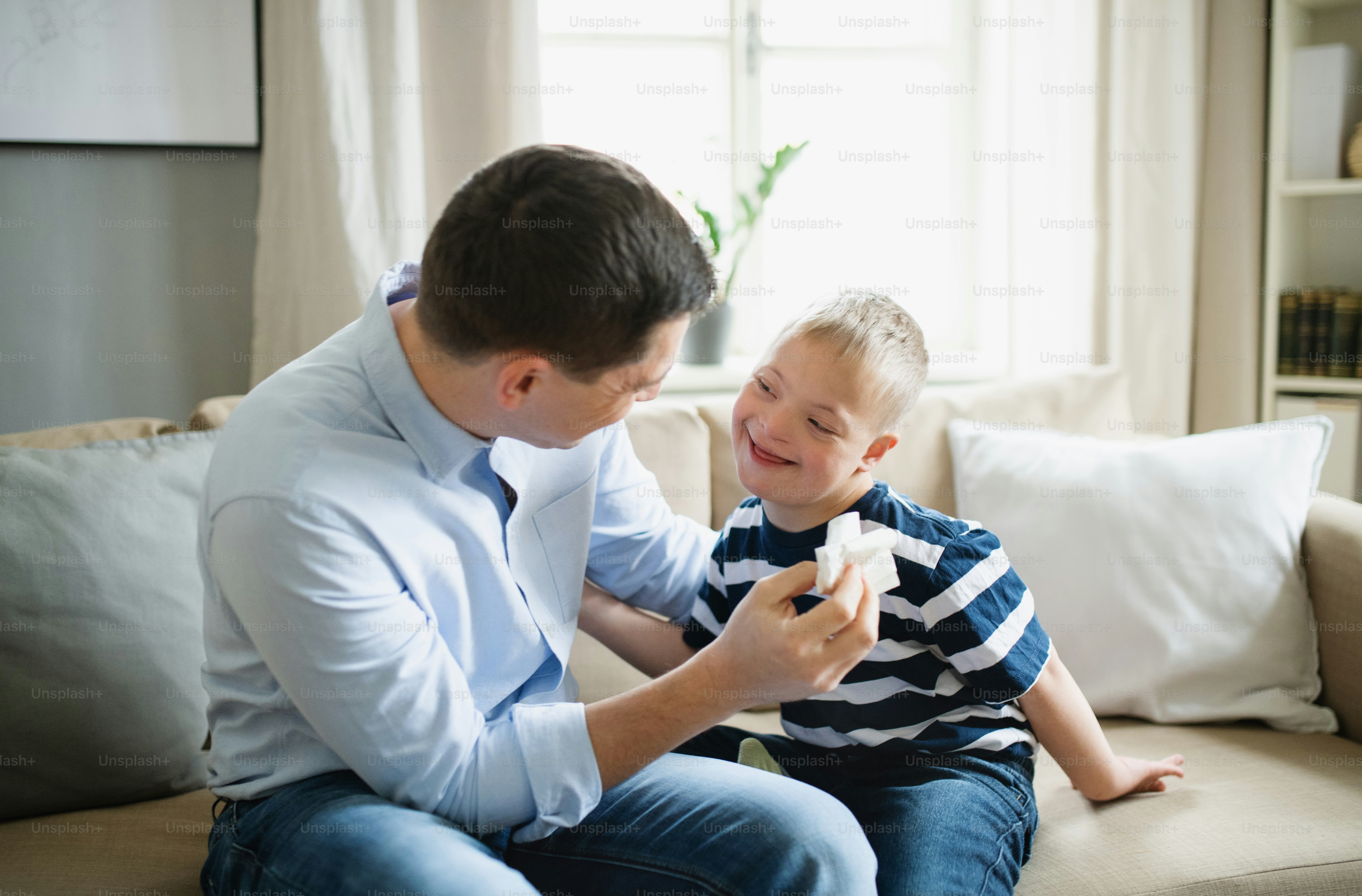 A father with happy down syndrome son indoors at home, talking. photo ...