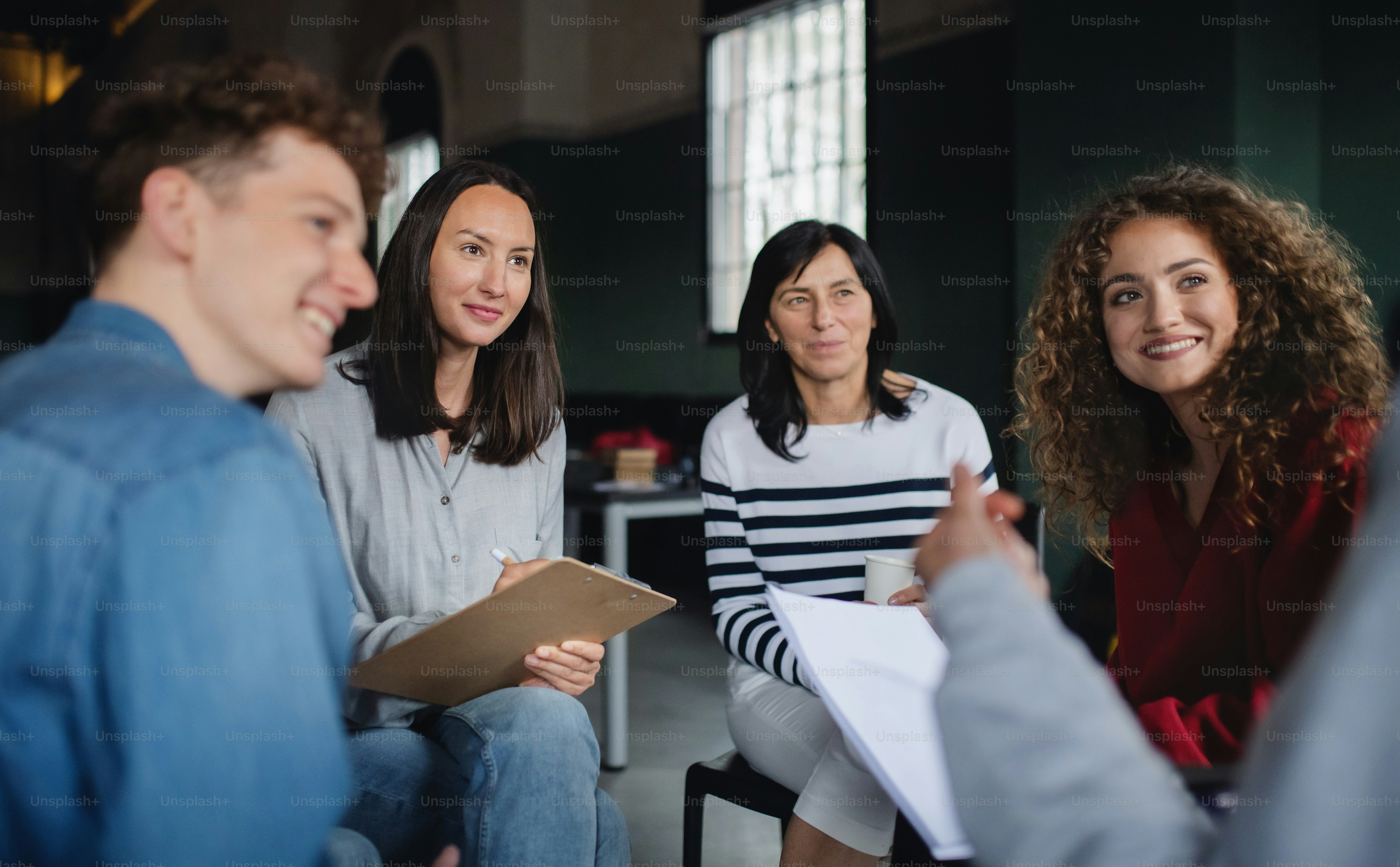 A counselor with men and women sitting in circle during group therapy ...