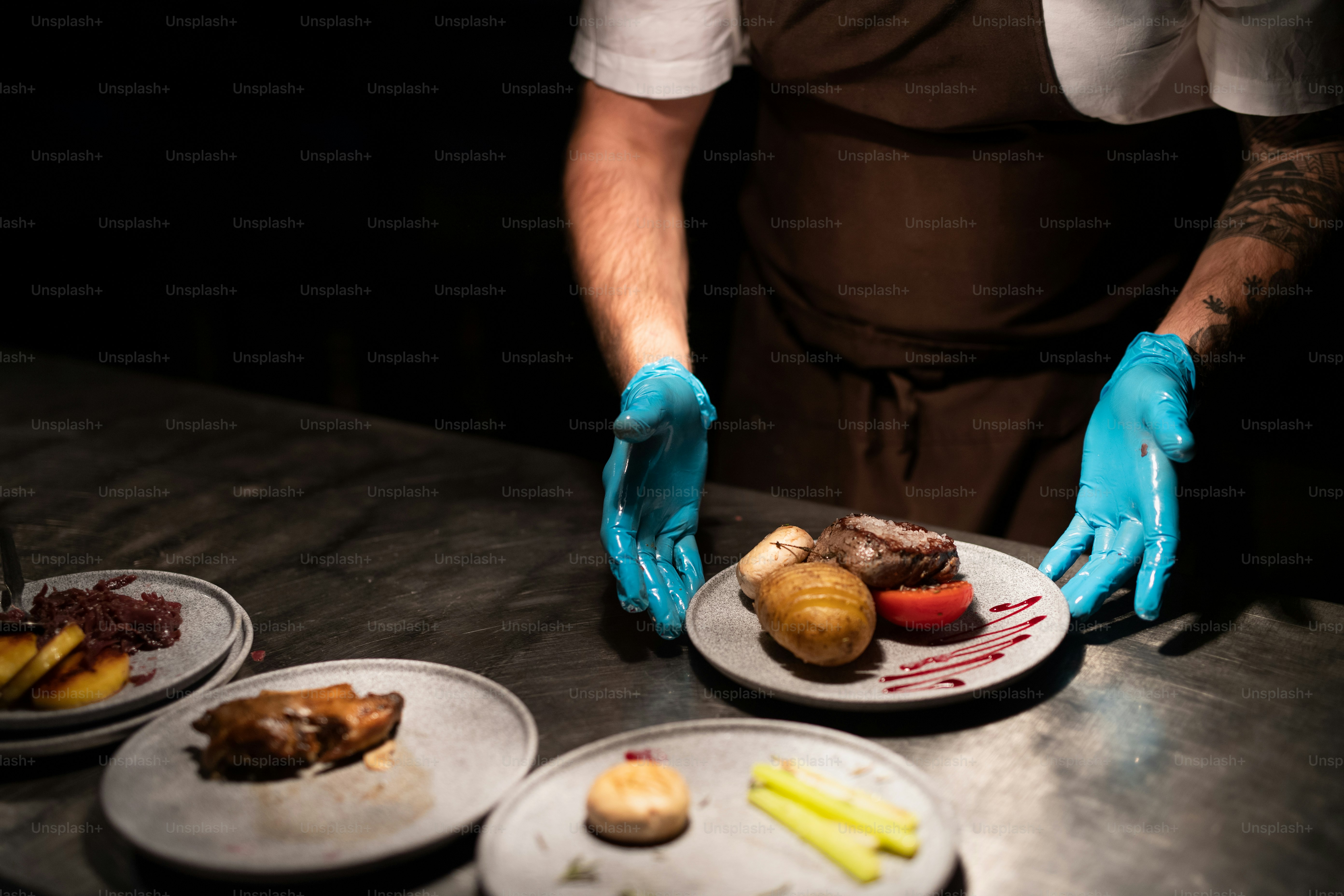Chef's hands in gloves serving and decorating his meal in restaurant ...