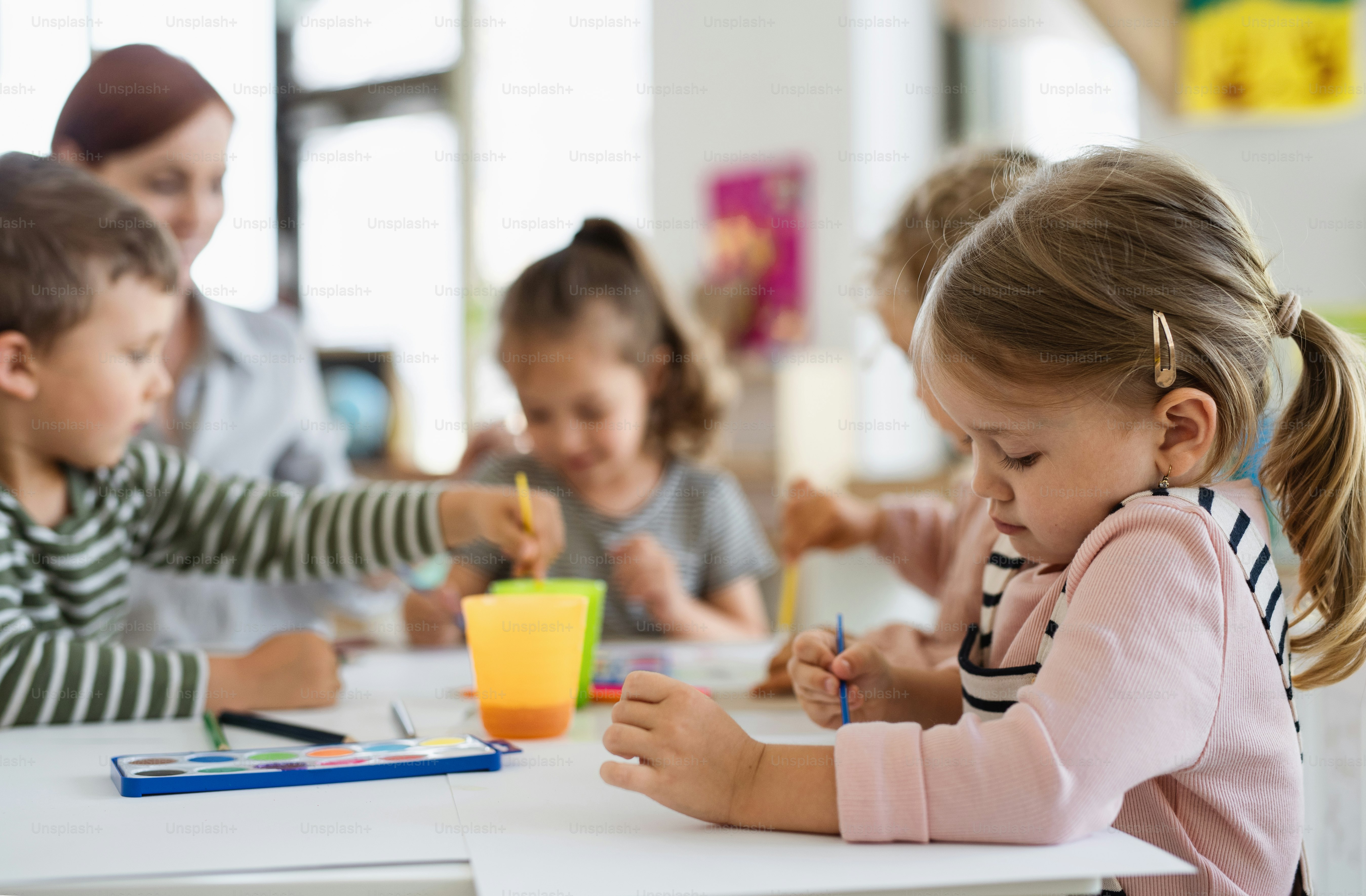 A group of small nursery school children with teacher indoors in ...