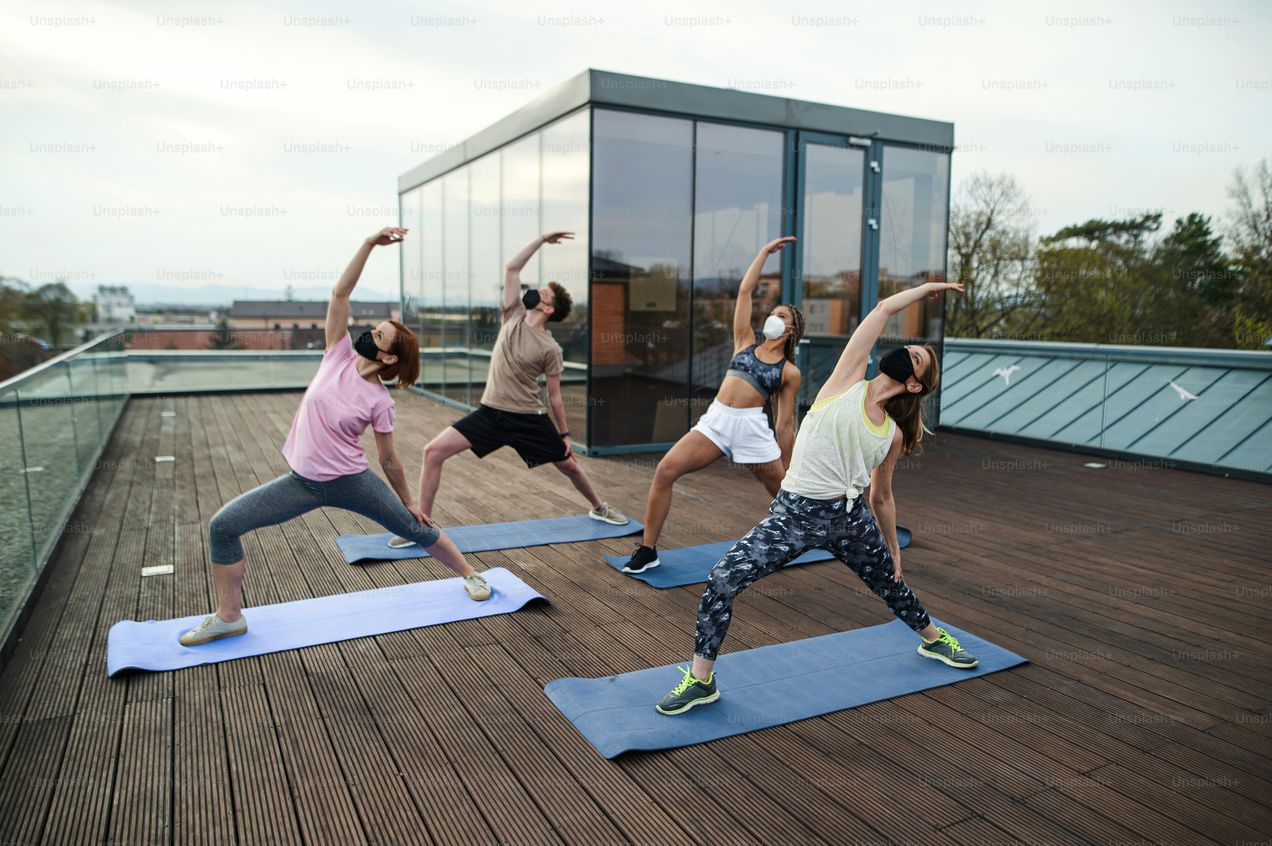 A group of young people doing exercise outdoors on terrace, sport and ...