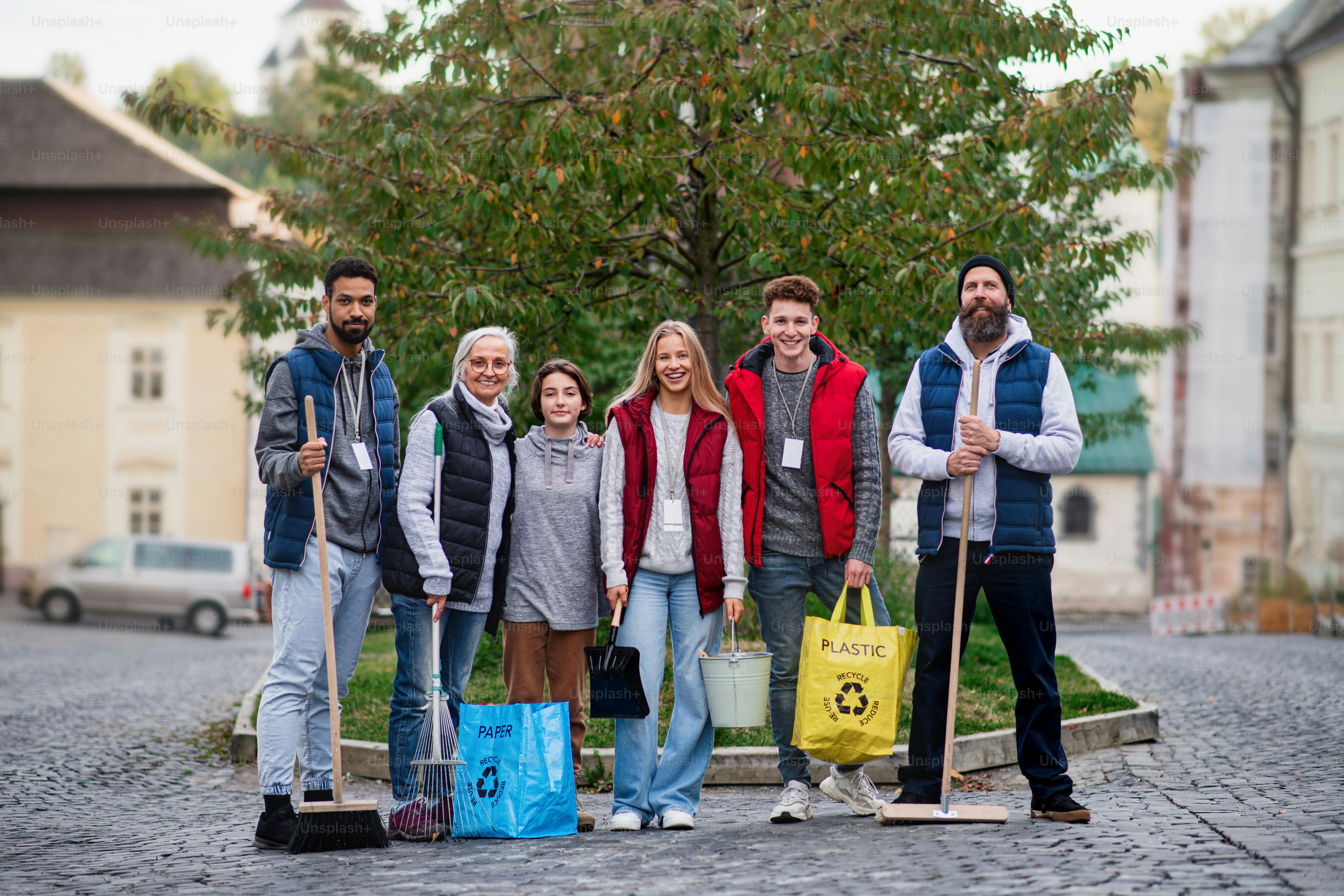 A group of happy volunteers looking at camera, ready to clean up street ...
