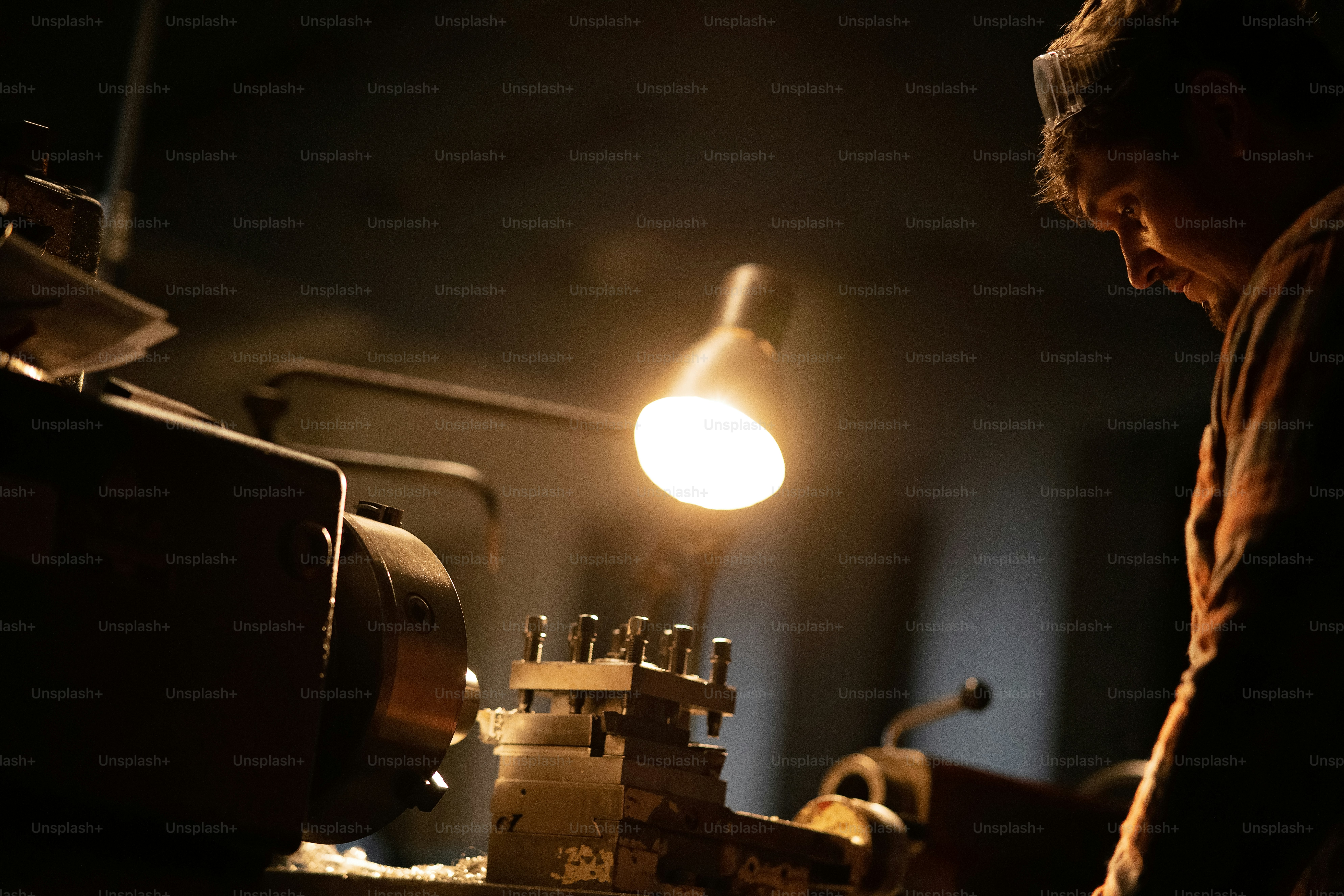 An industrial man working indoors in metal workshop at night. photo ...