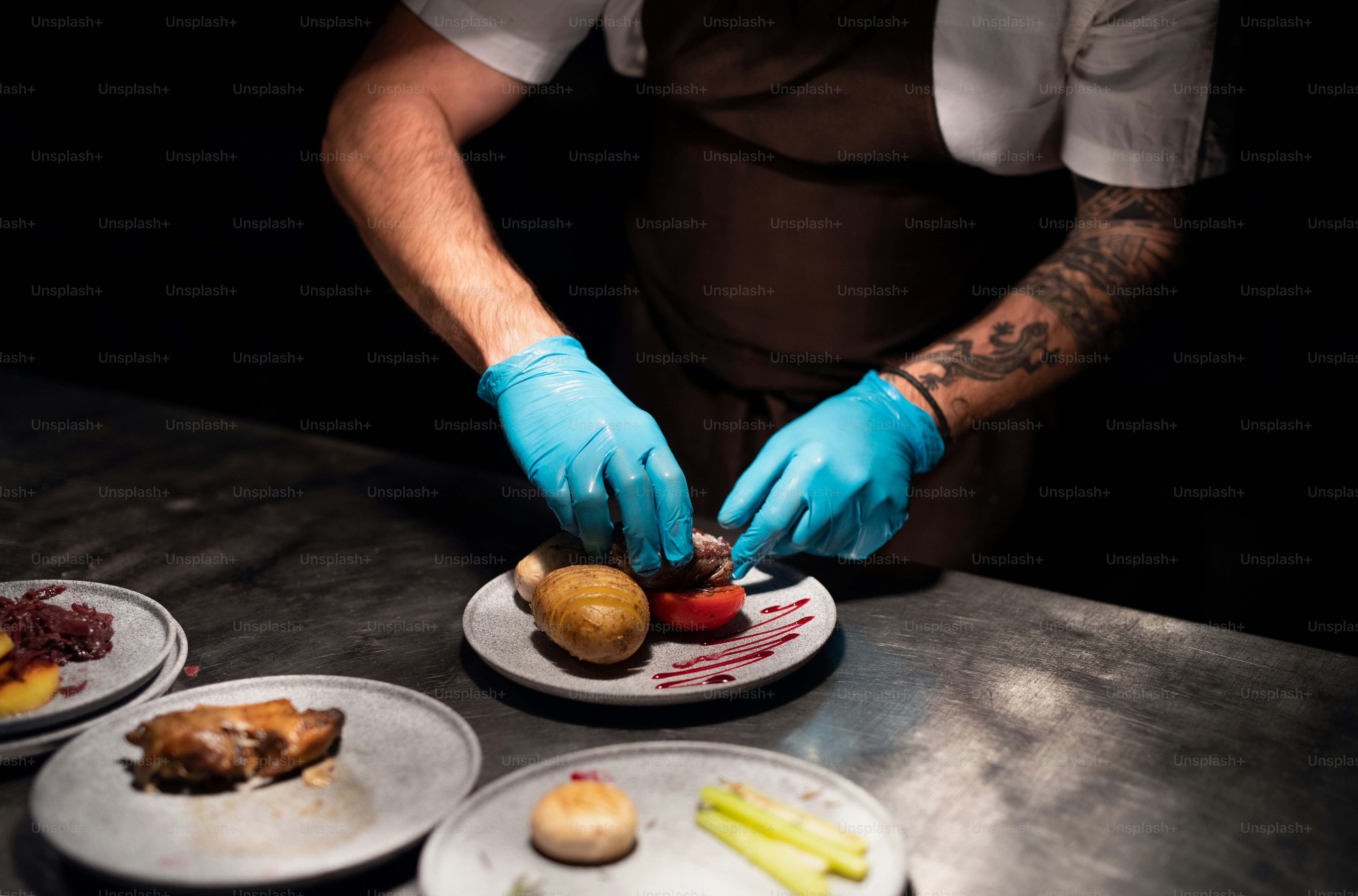 Chef's hands in gloves serving and decorating his meal in restaurant ...