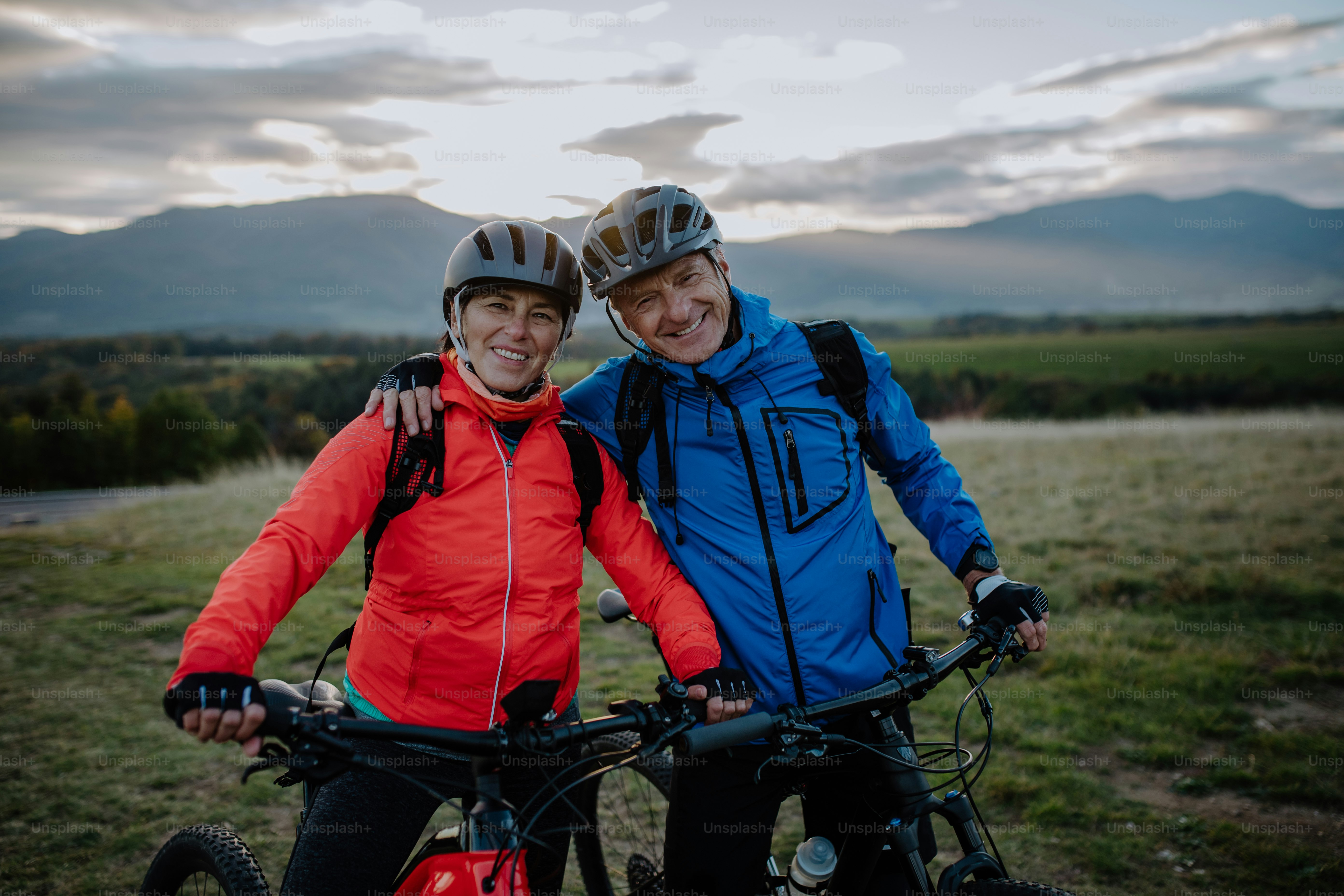 A happy senior couple bikers embracing outdoors in nature in autumn day ...