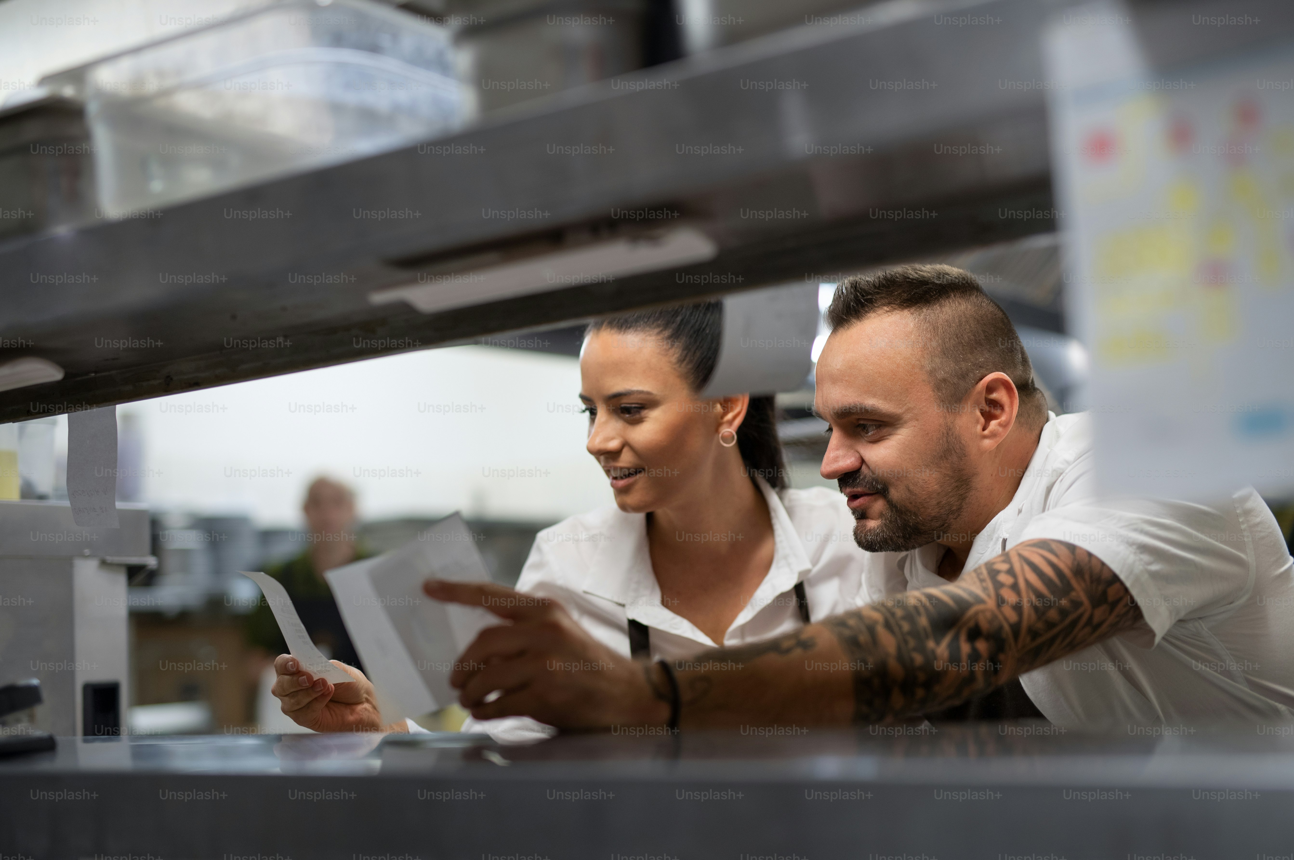 A chef and cook taking order slip in commercial kitchen. photo ...