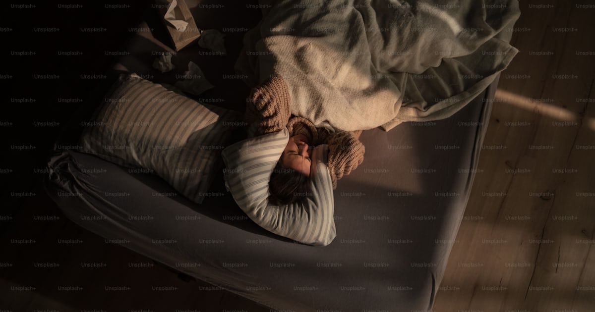 침대에 누워 있는 다중 인격 장애를 앓고 있는 슬픈 여성의 머리 위 모습 사진 Unsplash의 성인 이미지