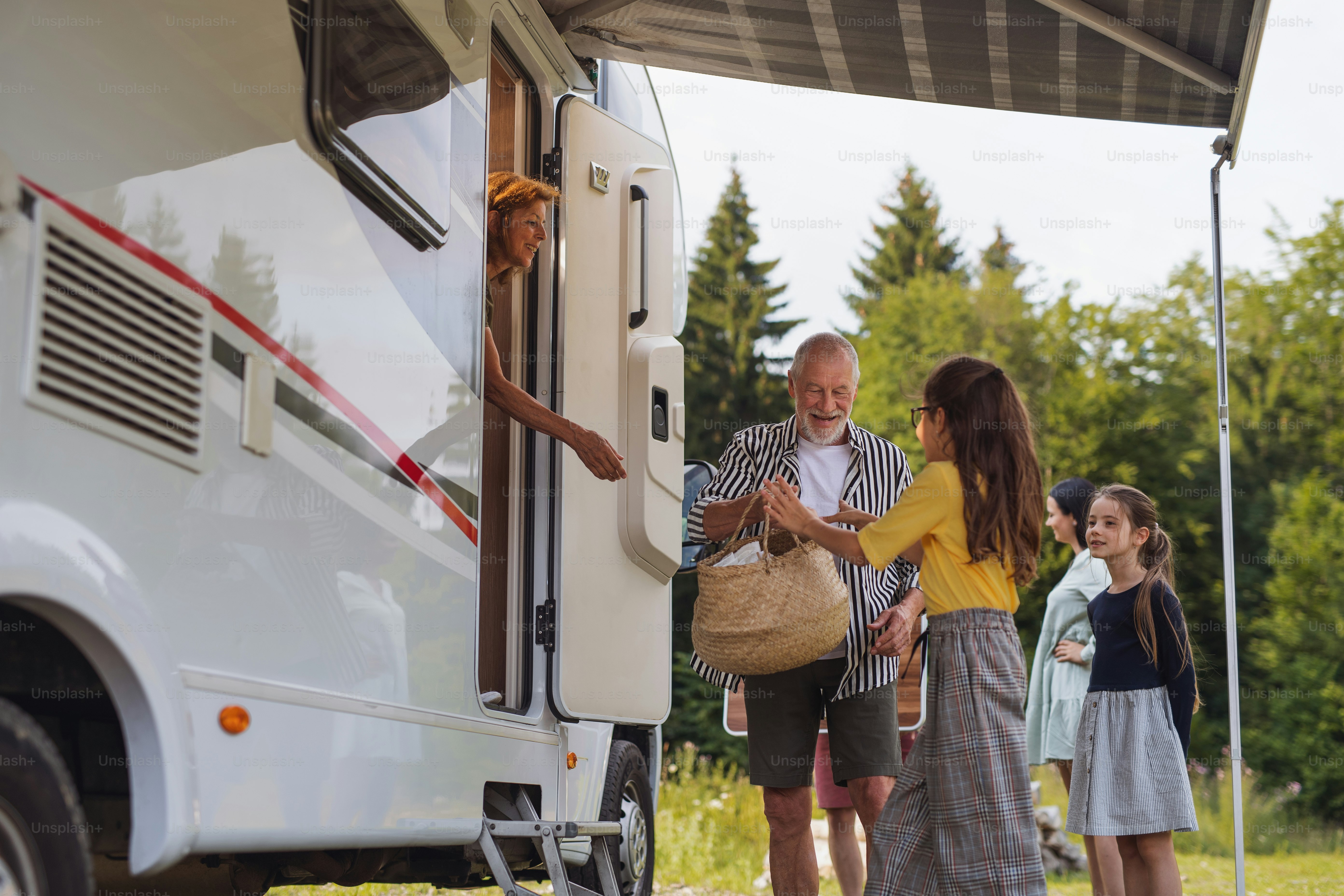 Happy multi-generation family unpacking and talking by car, caravan ...