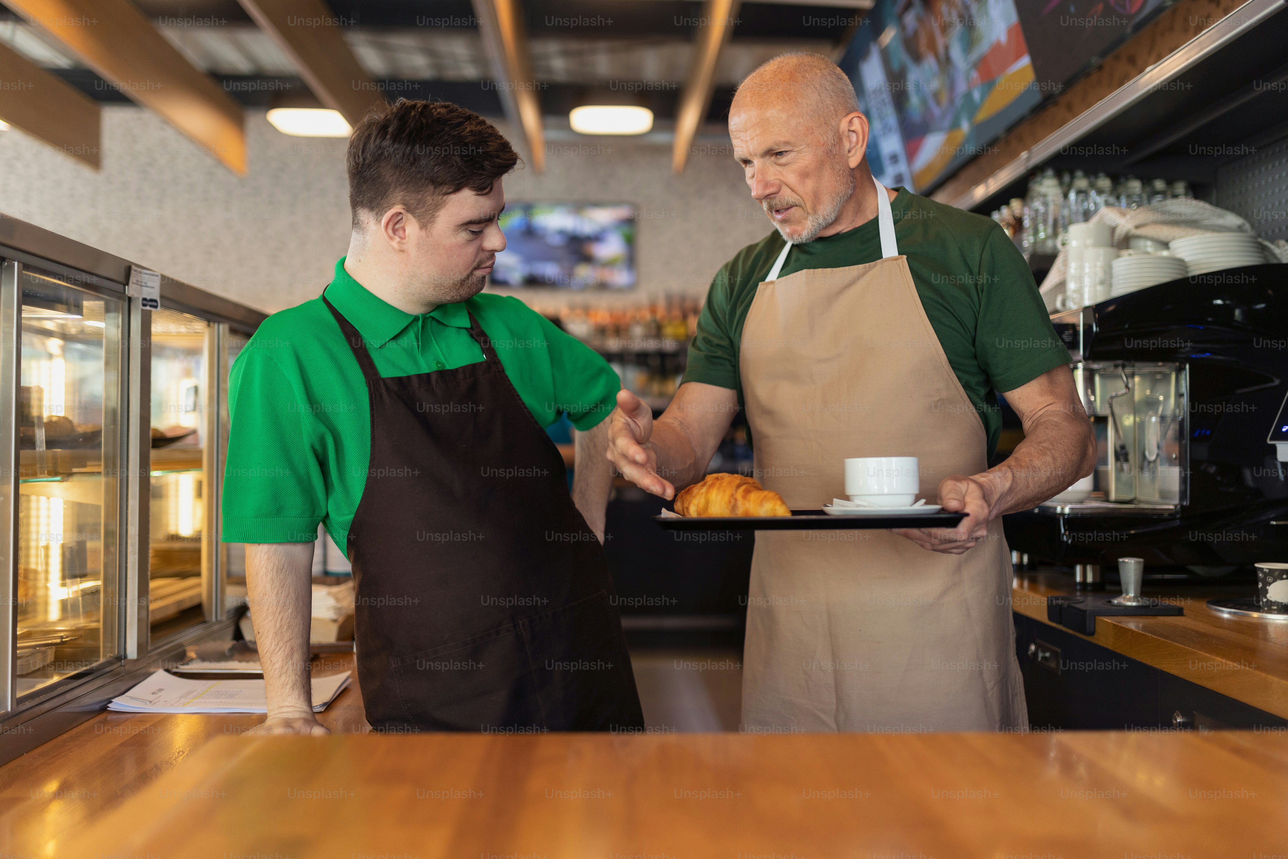 A happy waiter with Down syndrome serving coffee with help of his ...