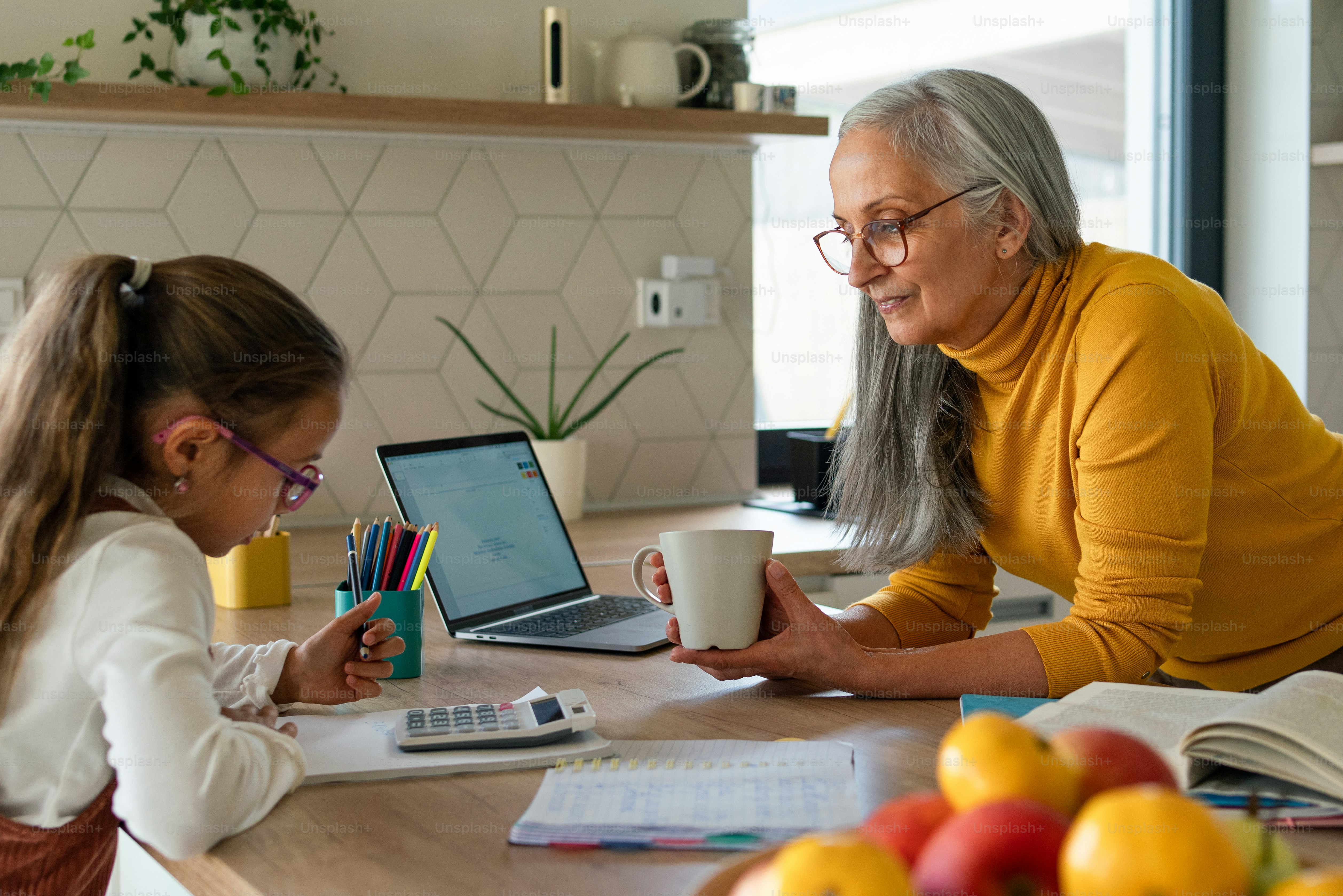 A small girl with senior grandmother doing homework at home. photo ...