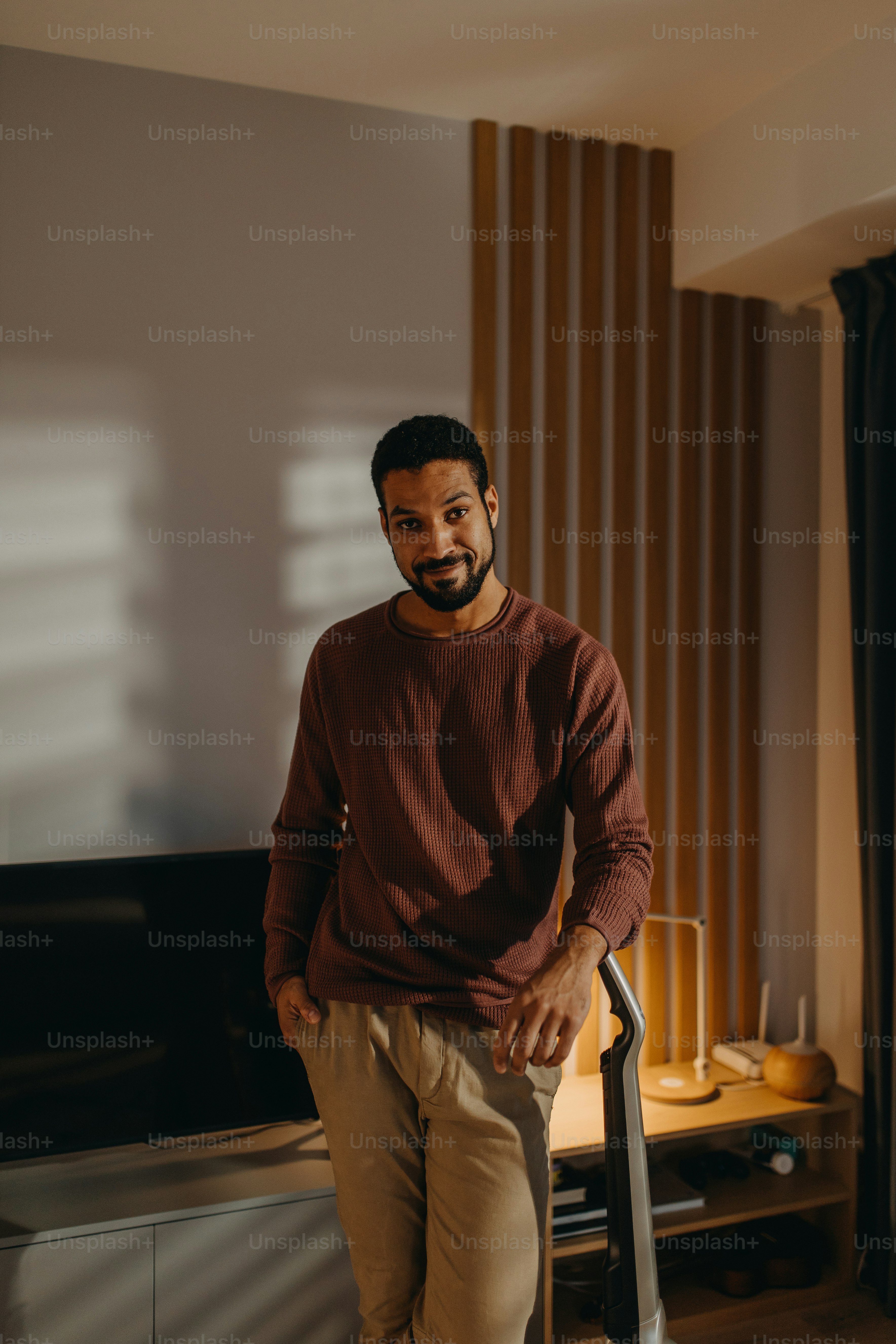 A young man hoovering carpet with vacuum cleaner in living room photo ...