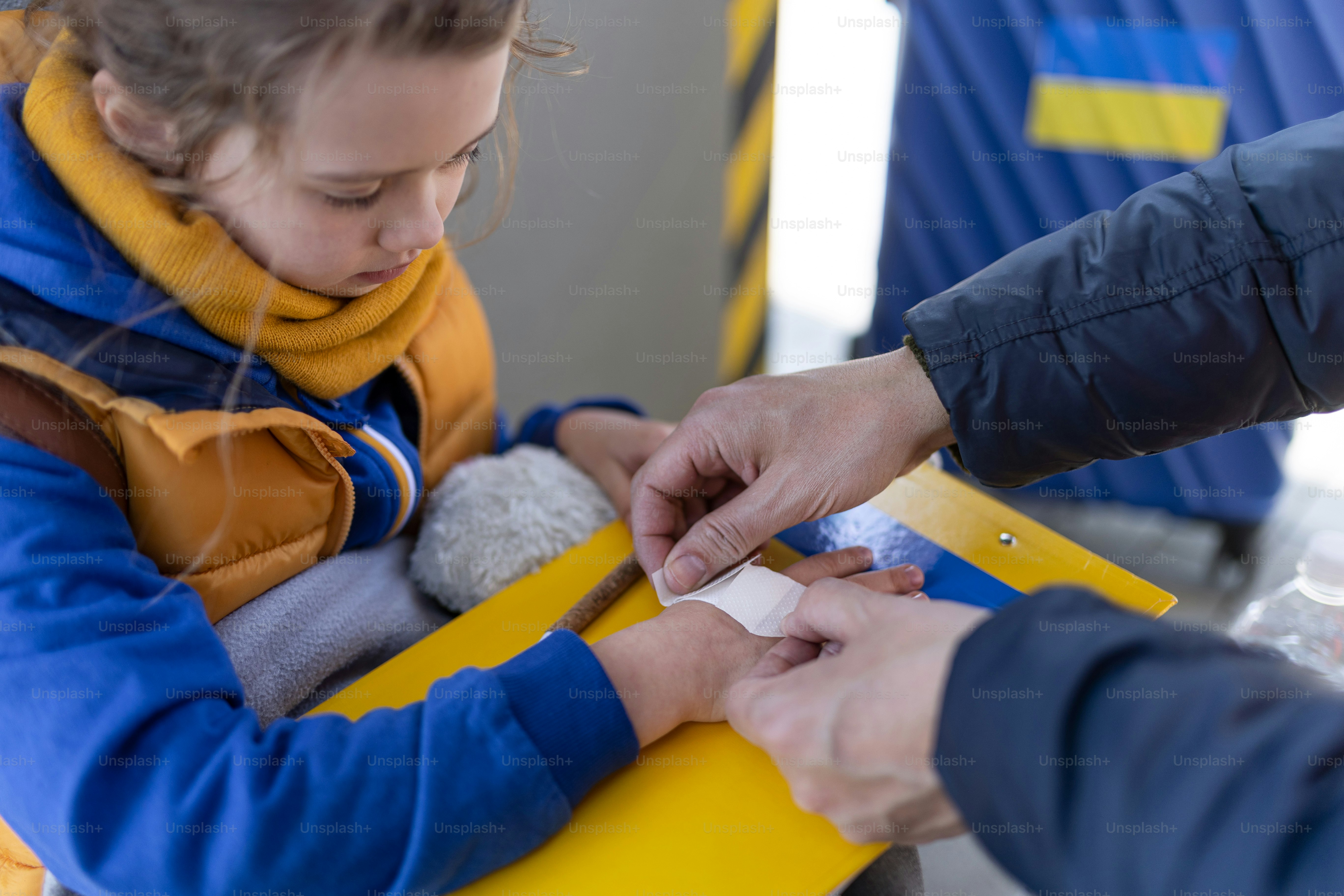 A volunteer helping Ukrainian refugee child at train station, giving ...