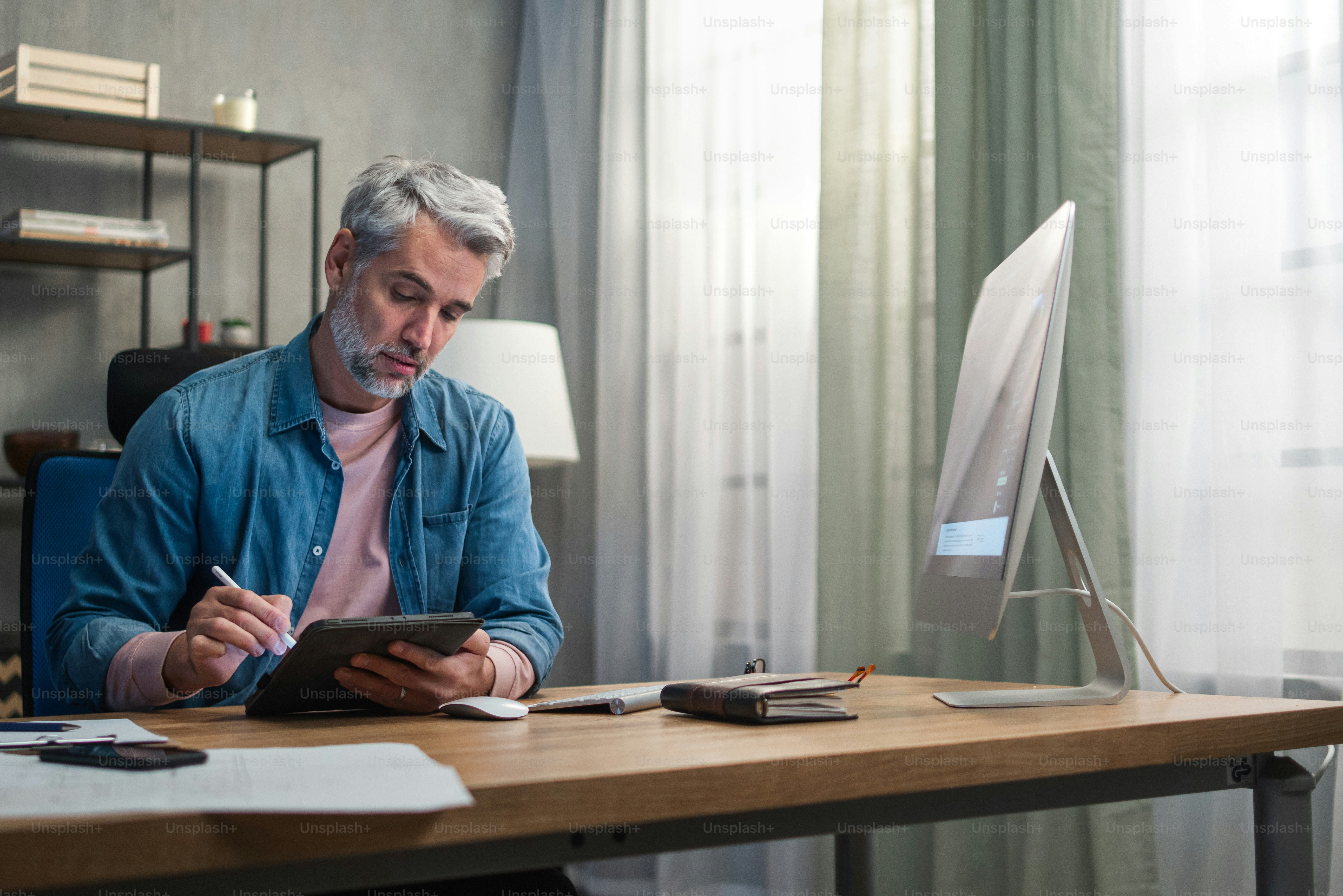 A mature man architect working on computer at desk indoors in office ...