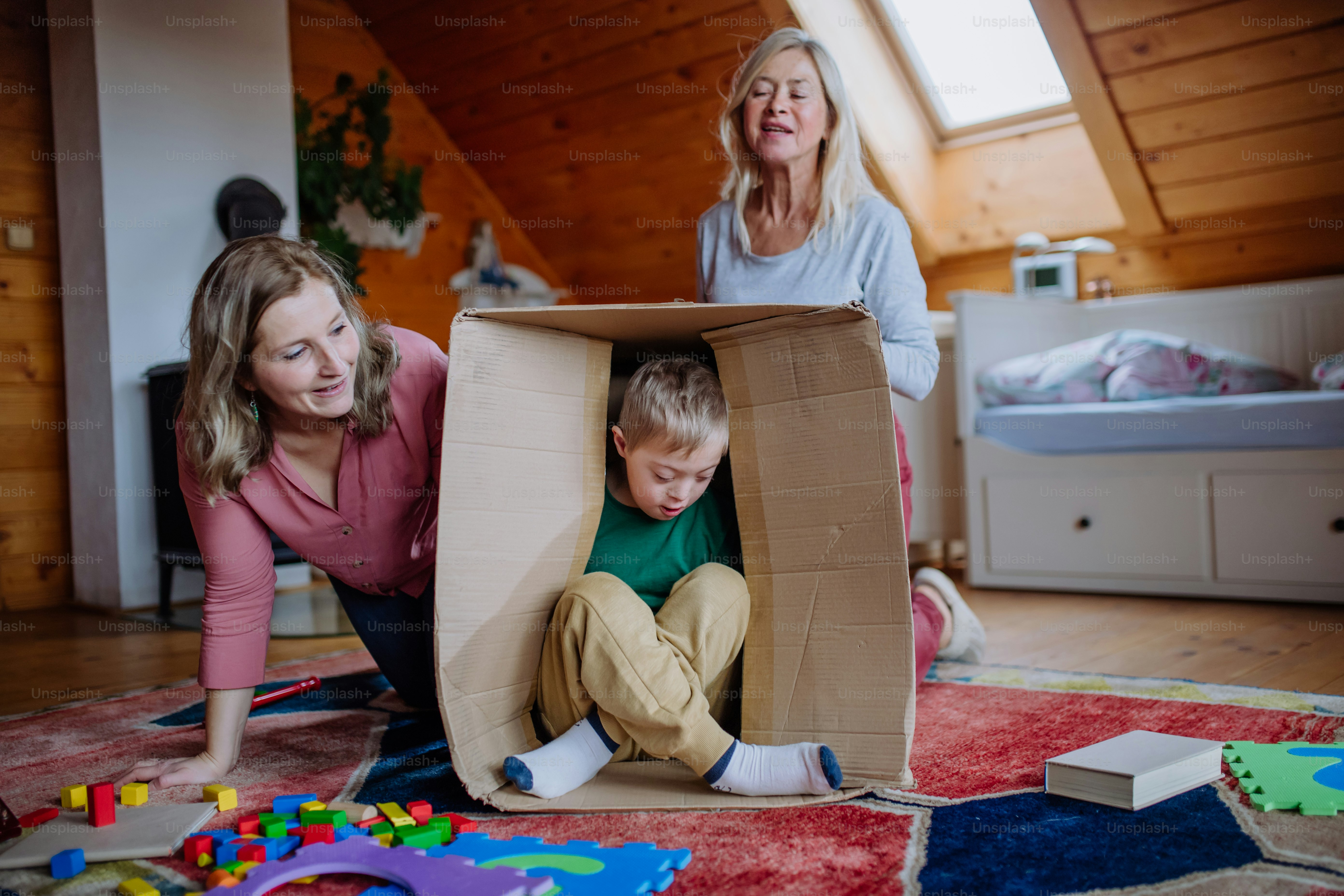 A boy with Down syndrome with his mother and grandmother playing with ...