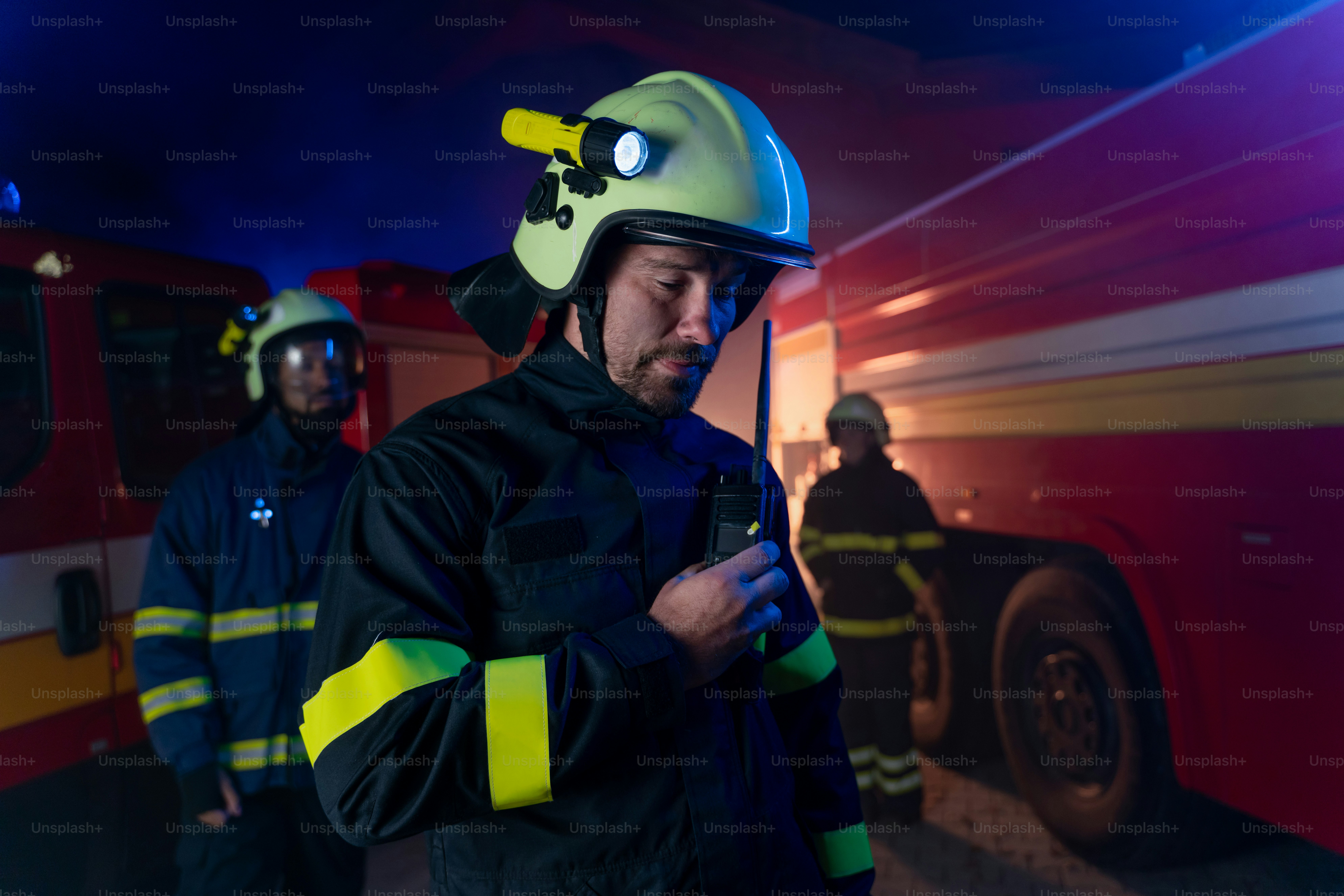 Firefighters men and woman looking at camera with a fire truck in ...